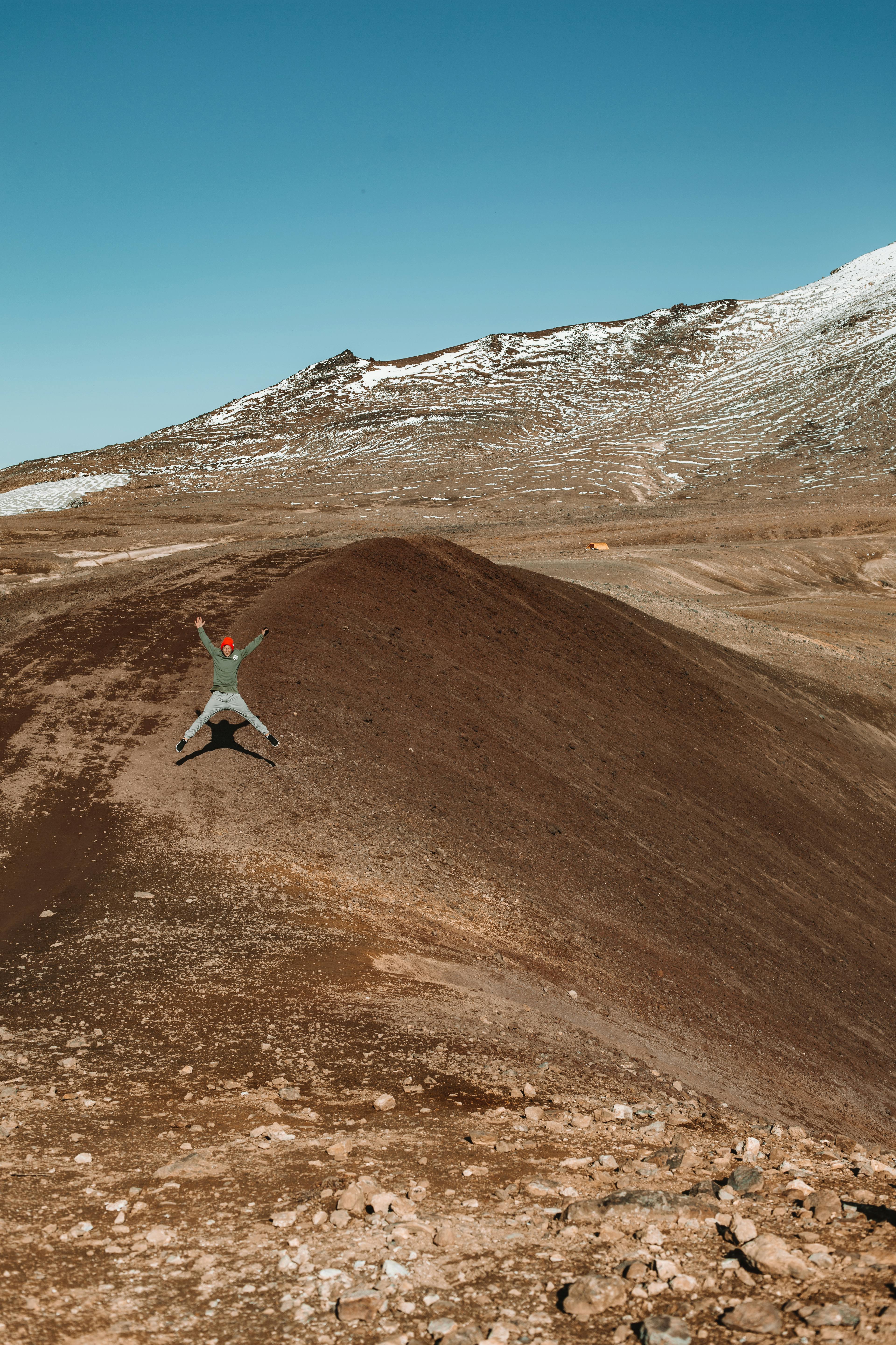 Woman jumping on mountain slope on sunny day · Free Stock Photo
