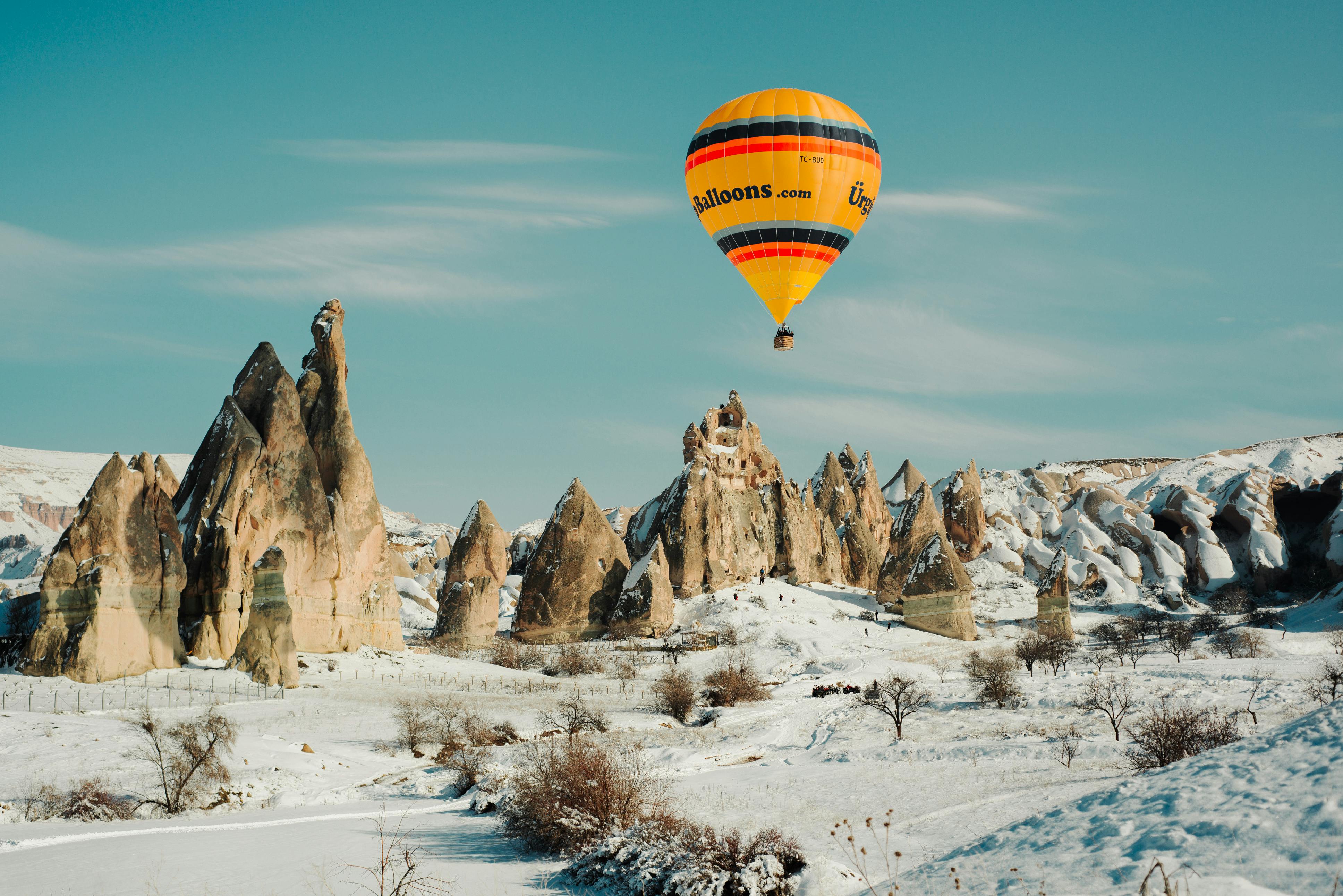 Yellow and Red Hot Air Balloon Flying Over Rock Formations · Free Stock ...