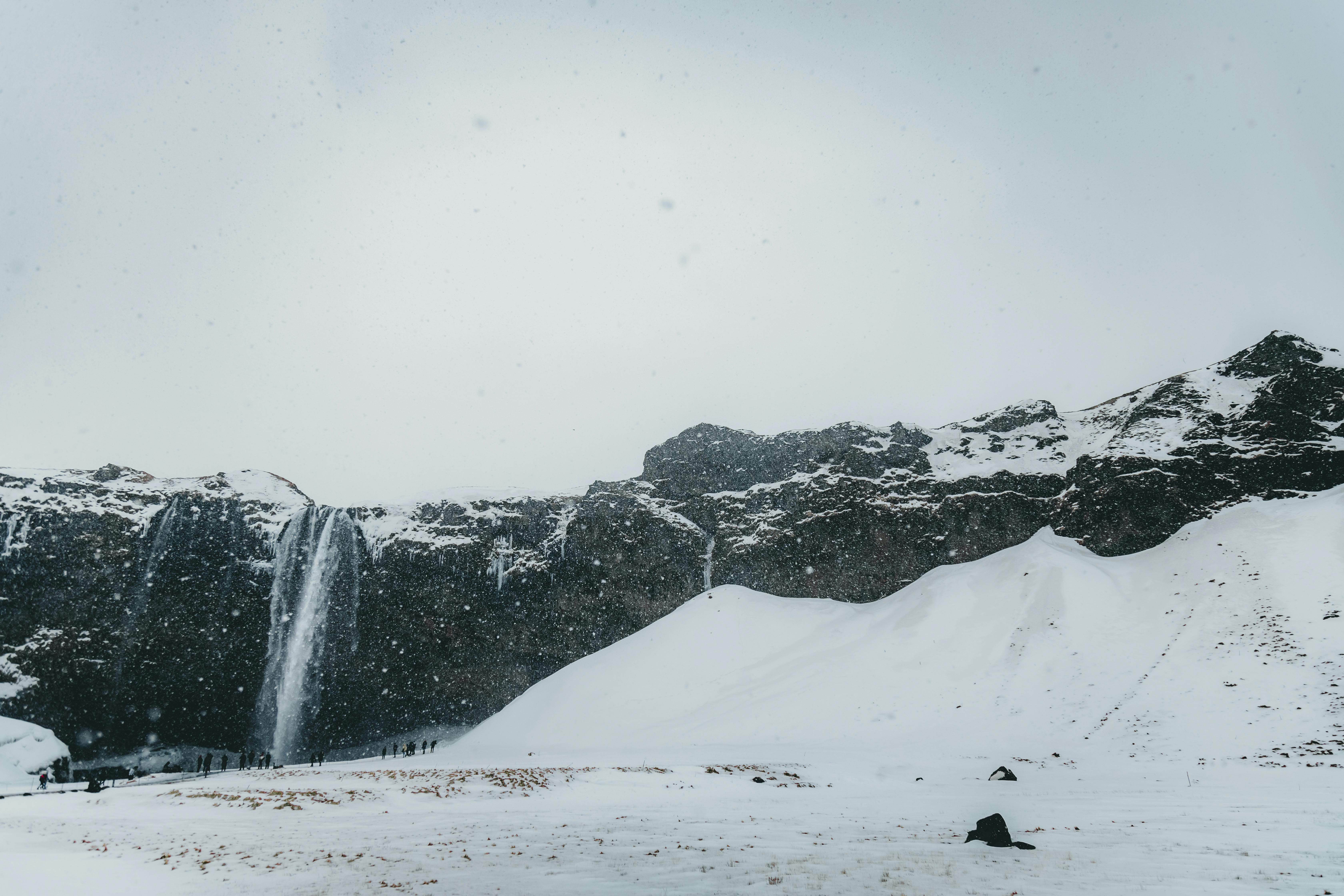 Snowy mountain ridge against overcast weather · Free Stock Photo