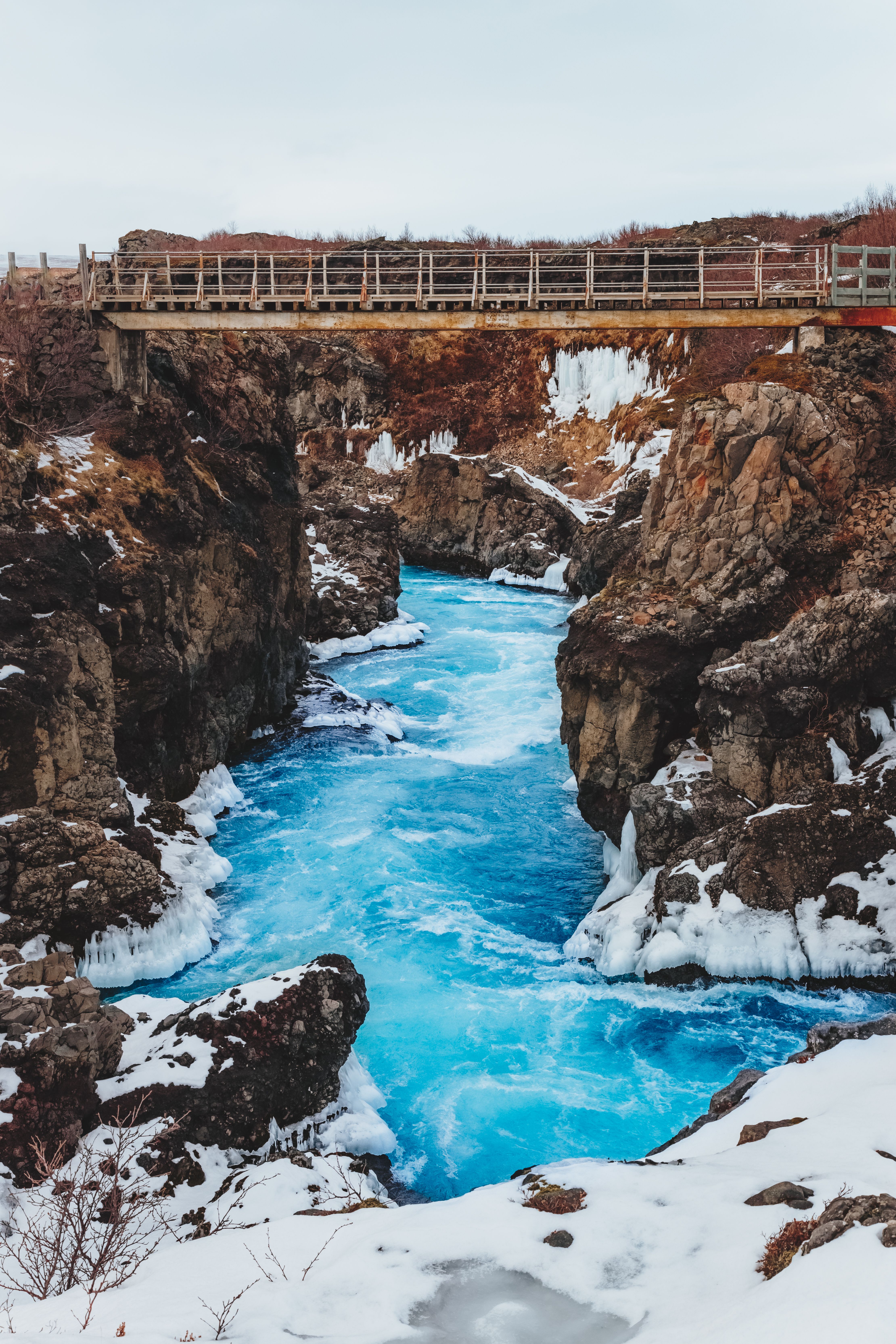 Blue river between rough cliffs under old bridge · Free Stock Photo