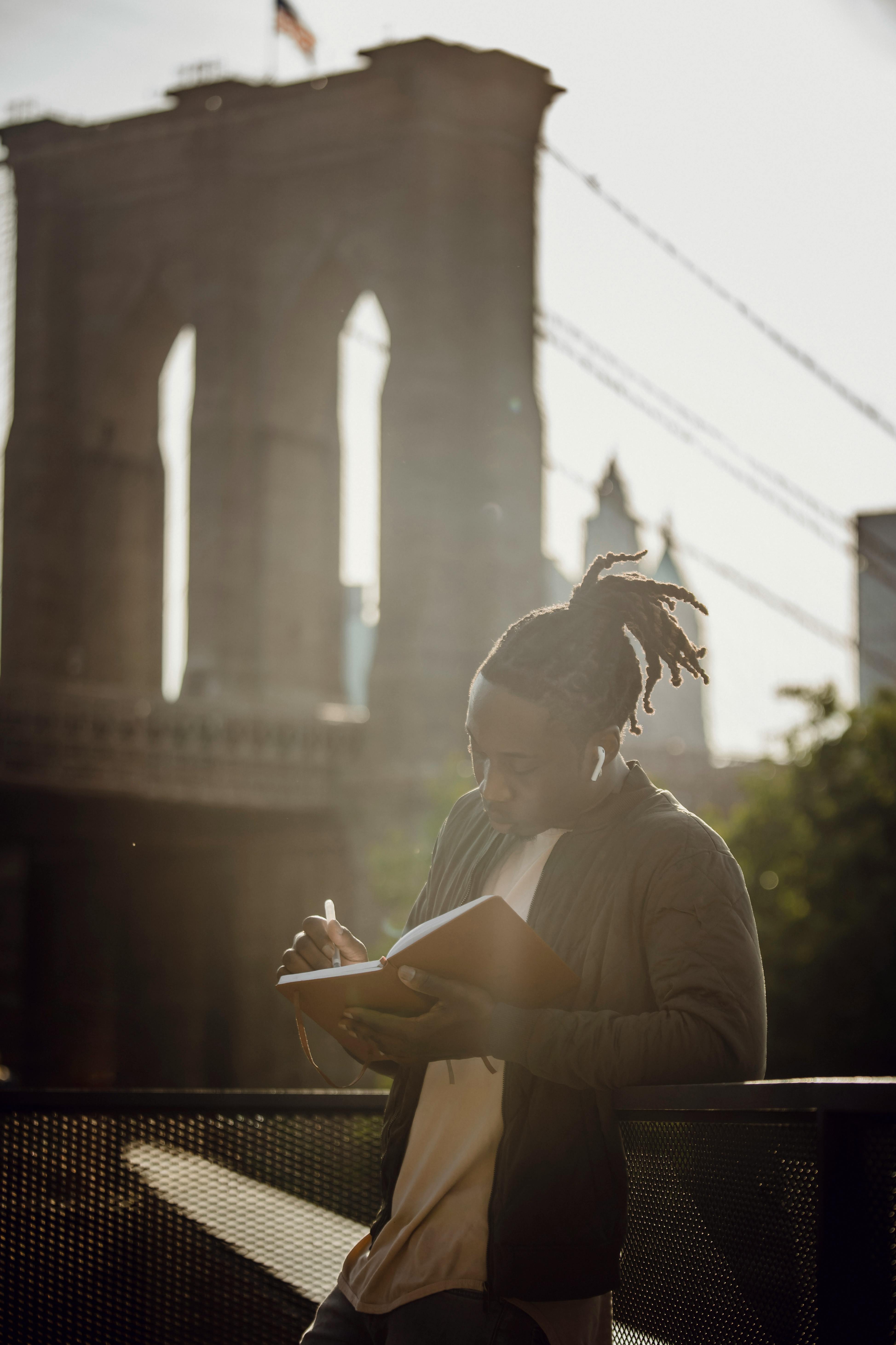 Young black man checking schedule in notebook while chilling on street ...