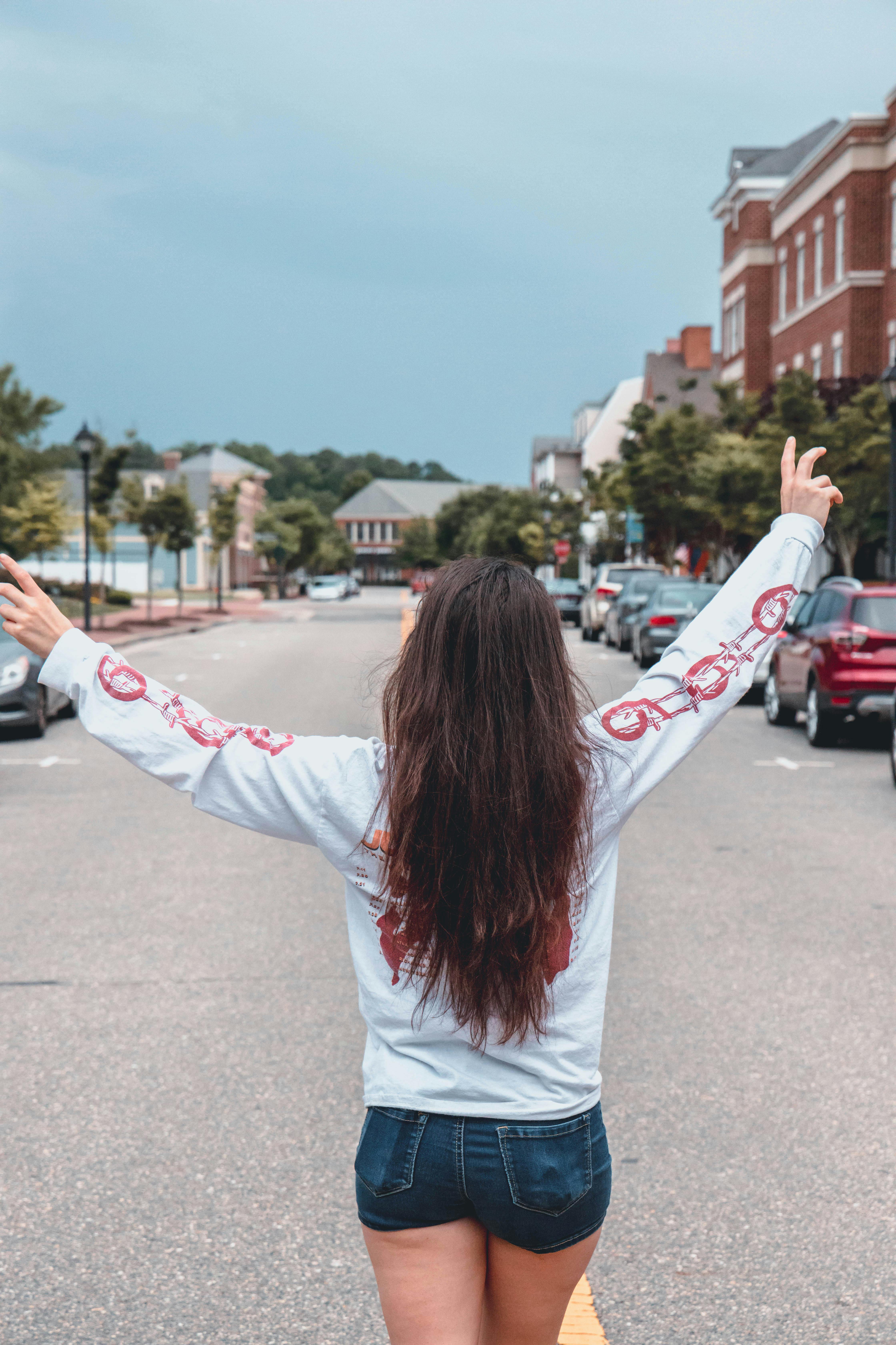 Anonymous lady with outstretched arms on street · Free Stock Photo
