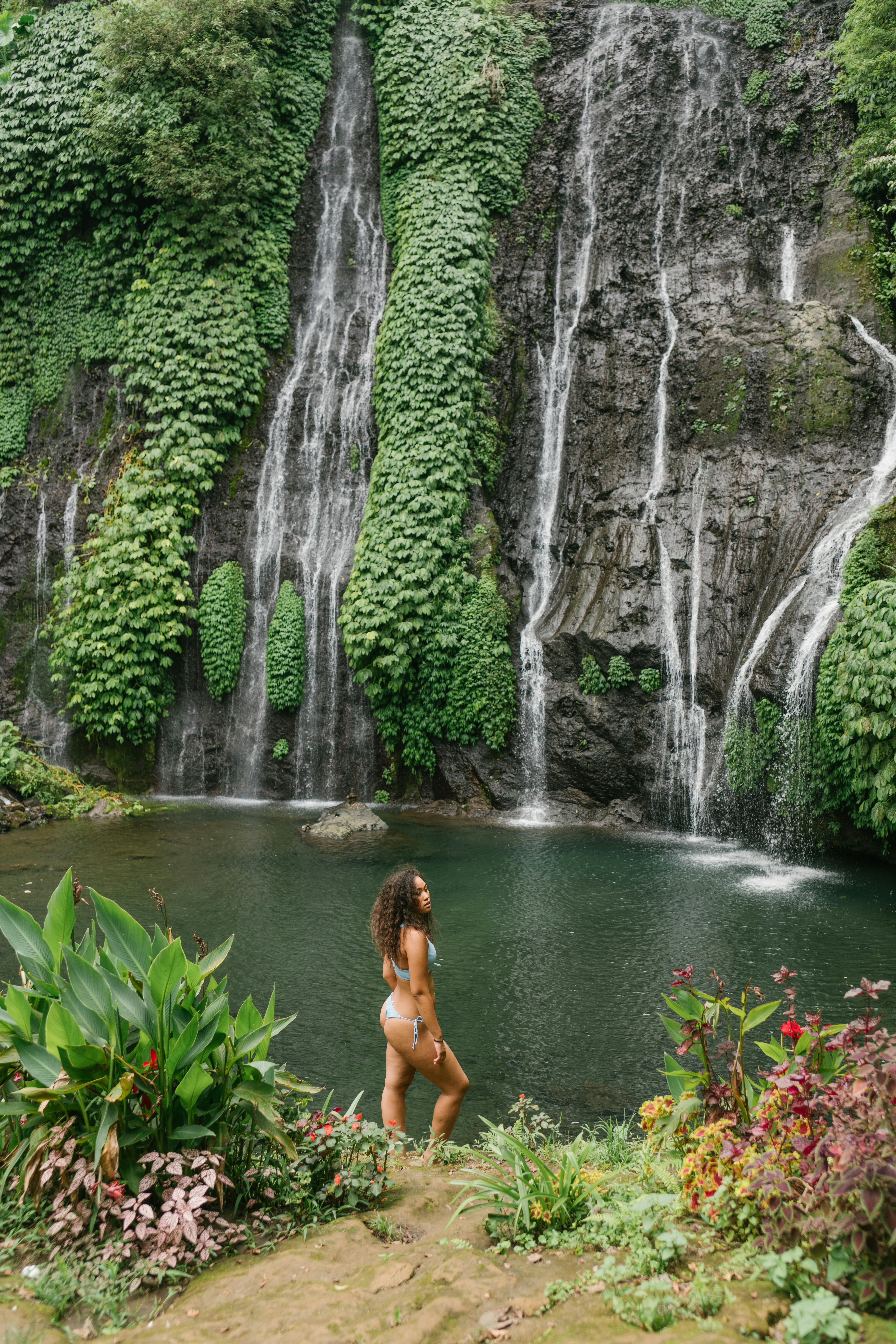 Relaxed woman in swimwear enjoying day in rainforest near waterfall ...