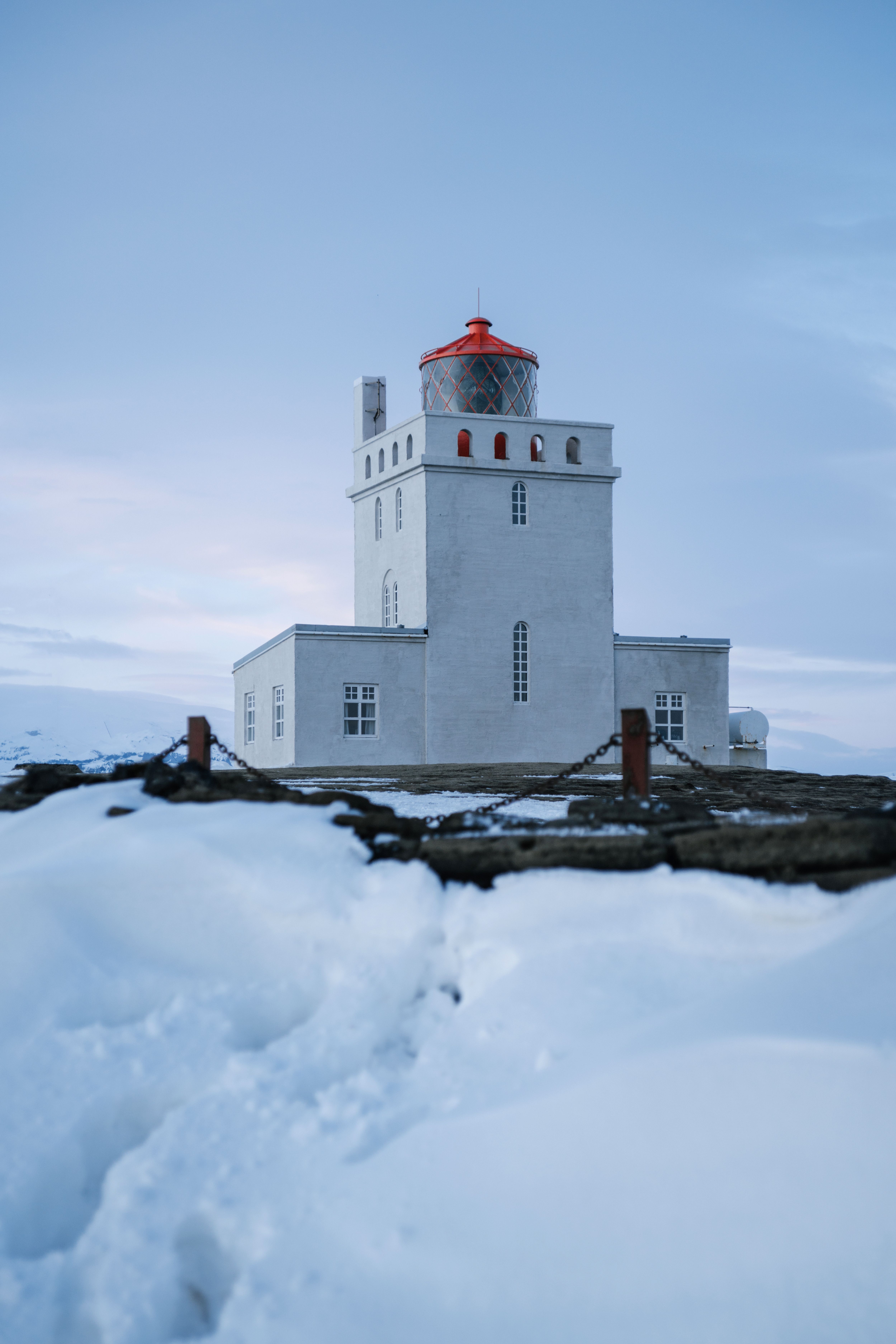 Dyrholaey Lighthouse on snowy ground on cloudy day · Free Stock Photo