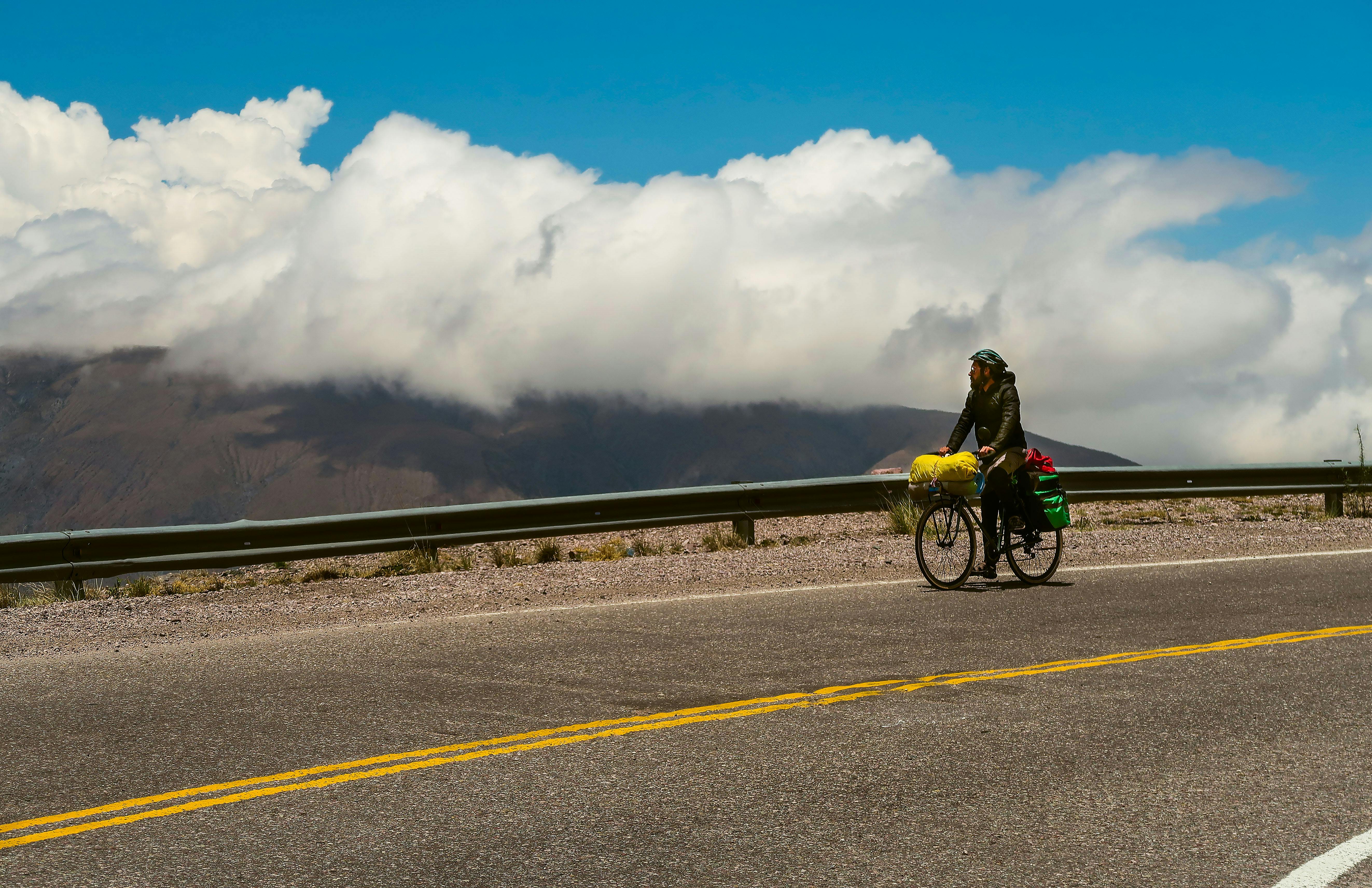 Anonymous cyclist riding bike along road in highland · Free Stock Photo