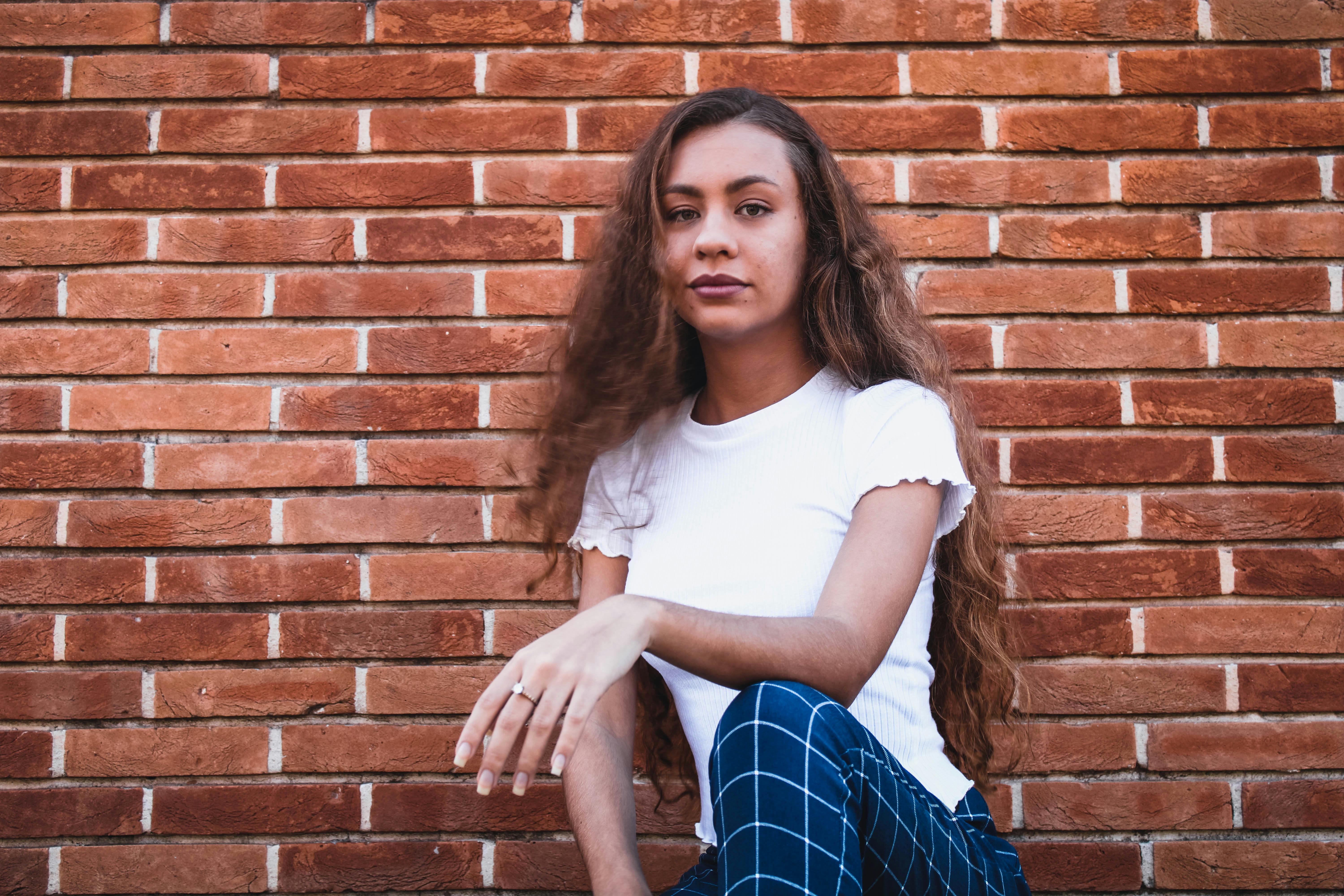Stylish young lady sitting on haunches near brick building · Free Stock ...