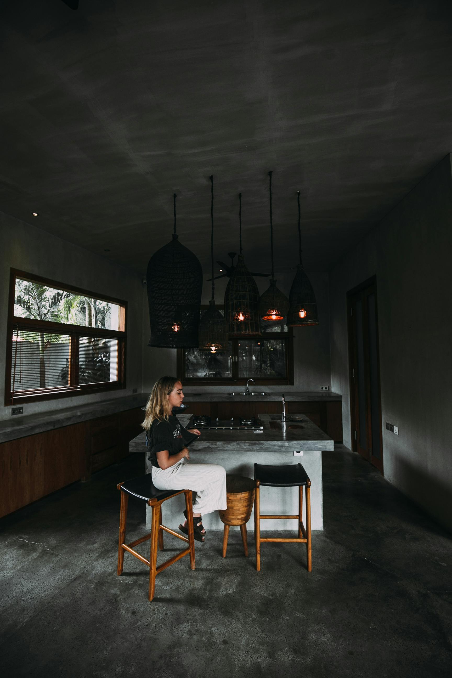 Melancholic woman resting on stool in dark kitchen · Free Stock Photo