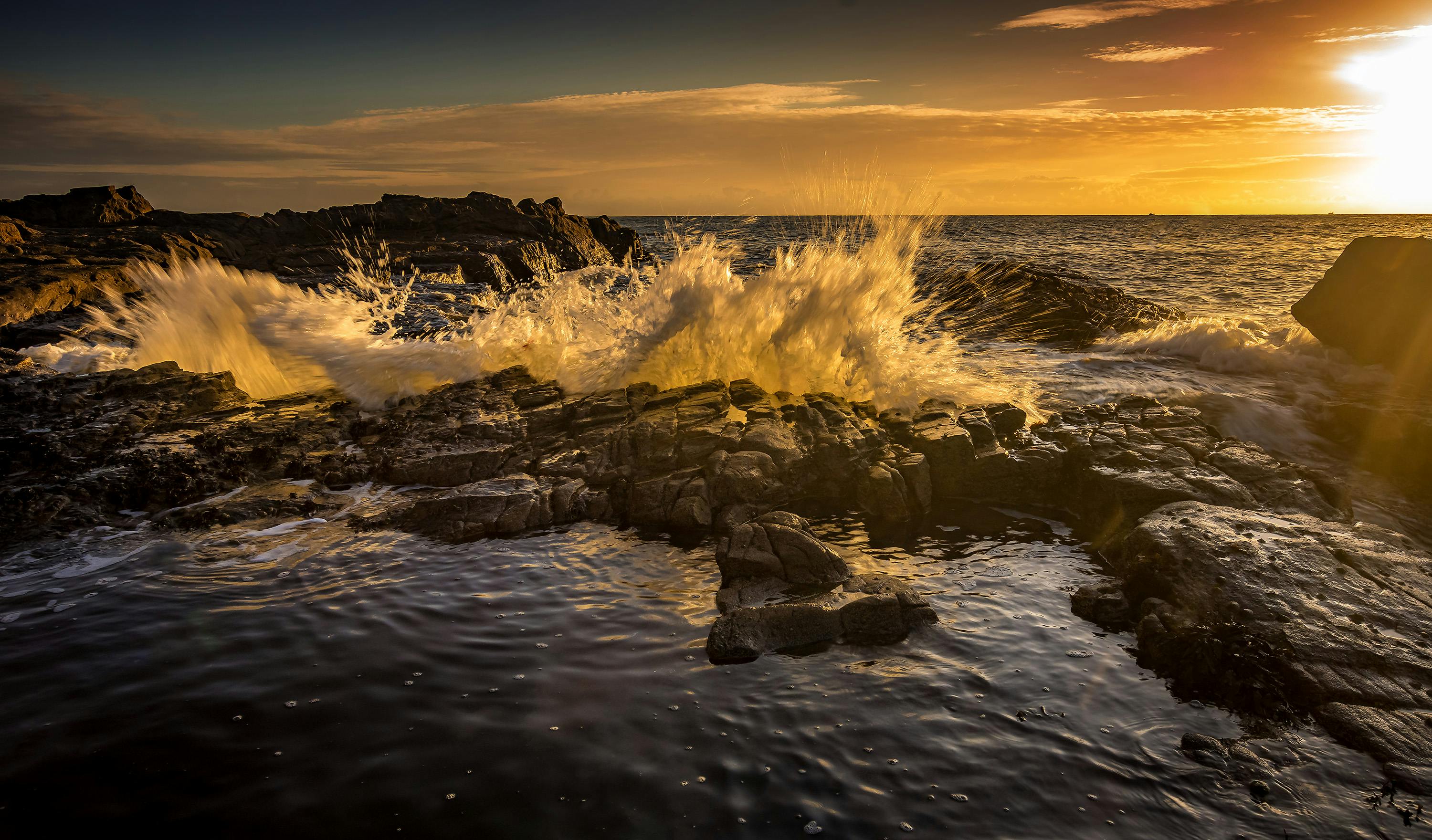 Splashing sea water near stones at colorful sunset · Free Stock Photo