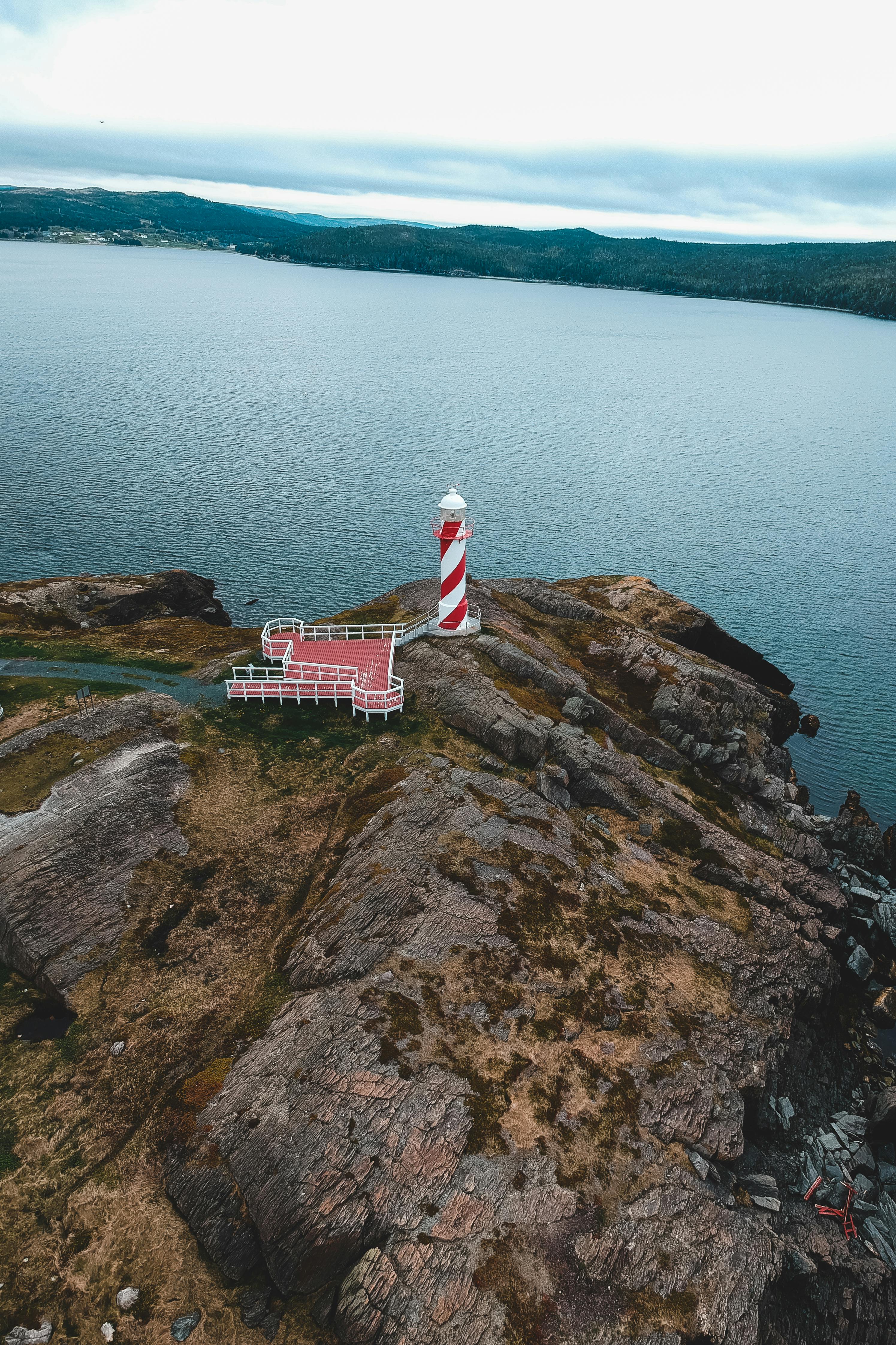 Bright lighthouse on rough mountain near sea · Free Stock Photo
