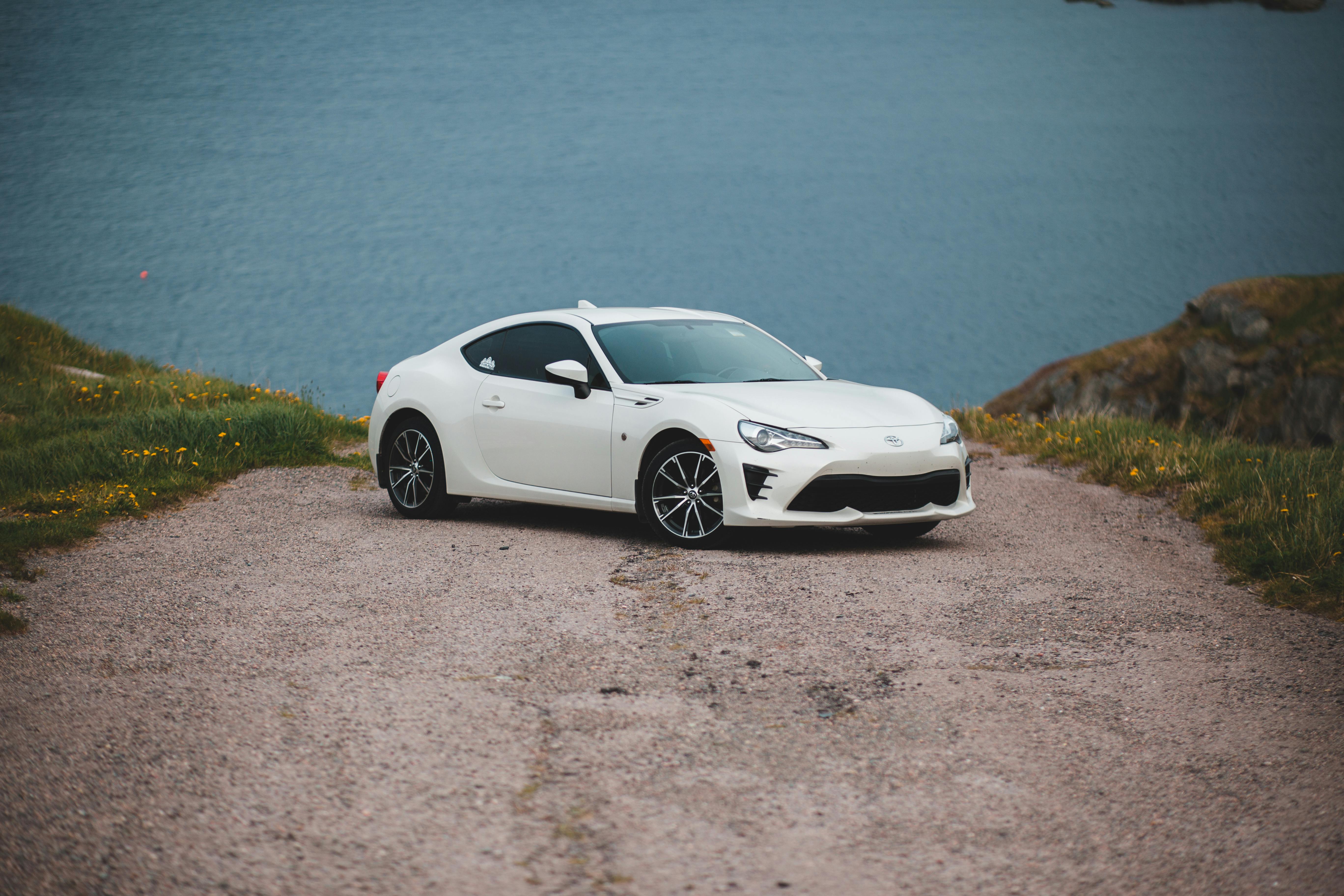 Modern car on gravel road against sea · Free Stock Photo
