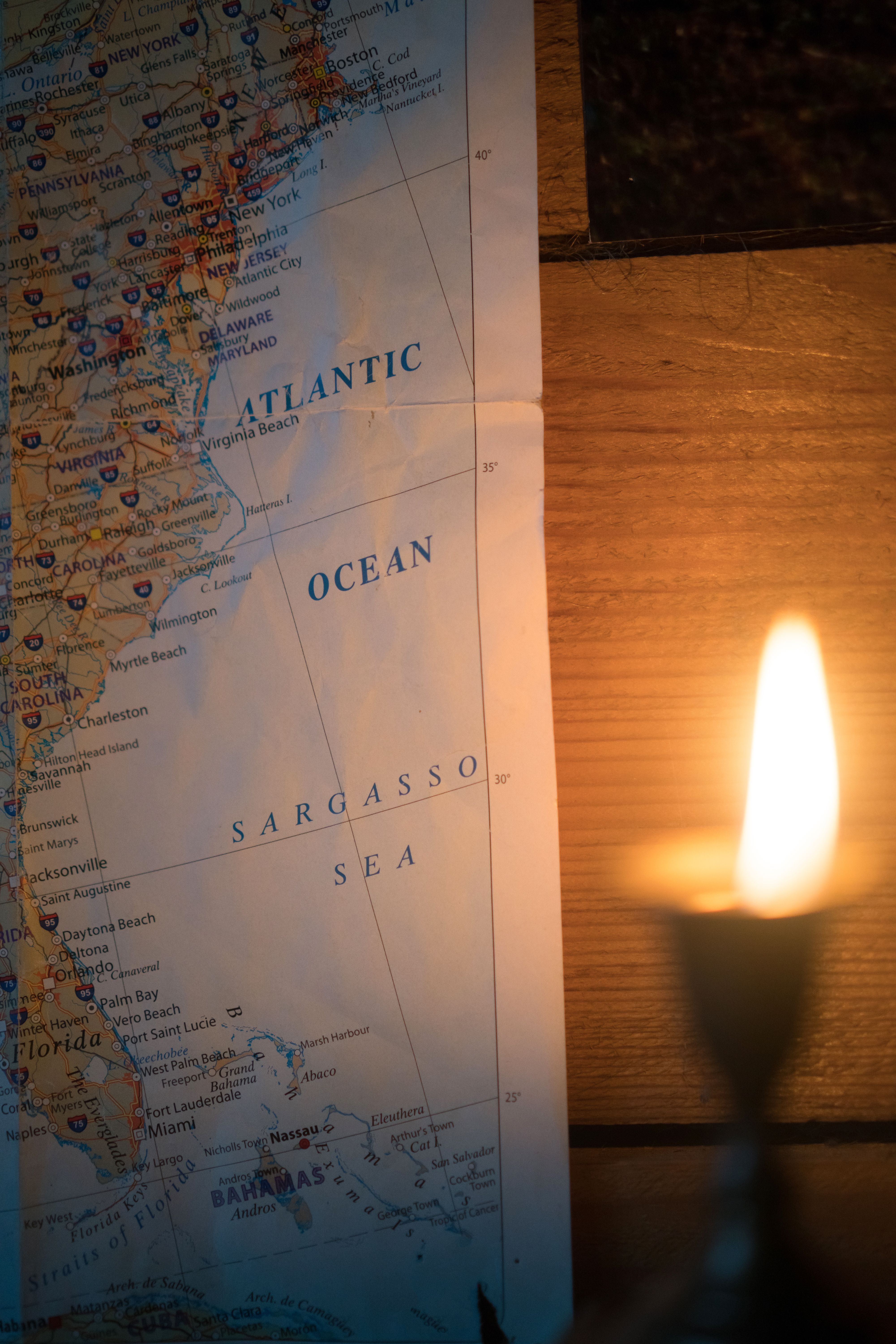 A Candle Lighting the Map on the Wooden Wall · Free Stock Photo