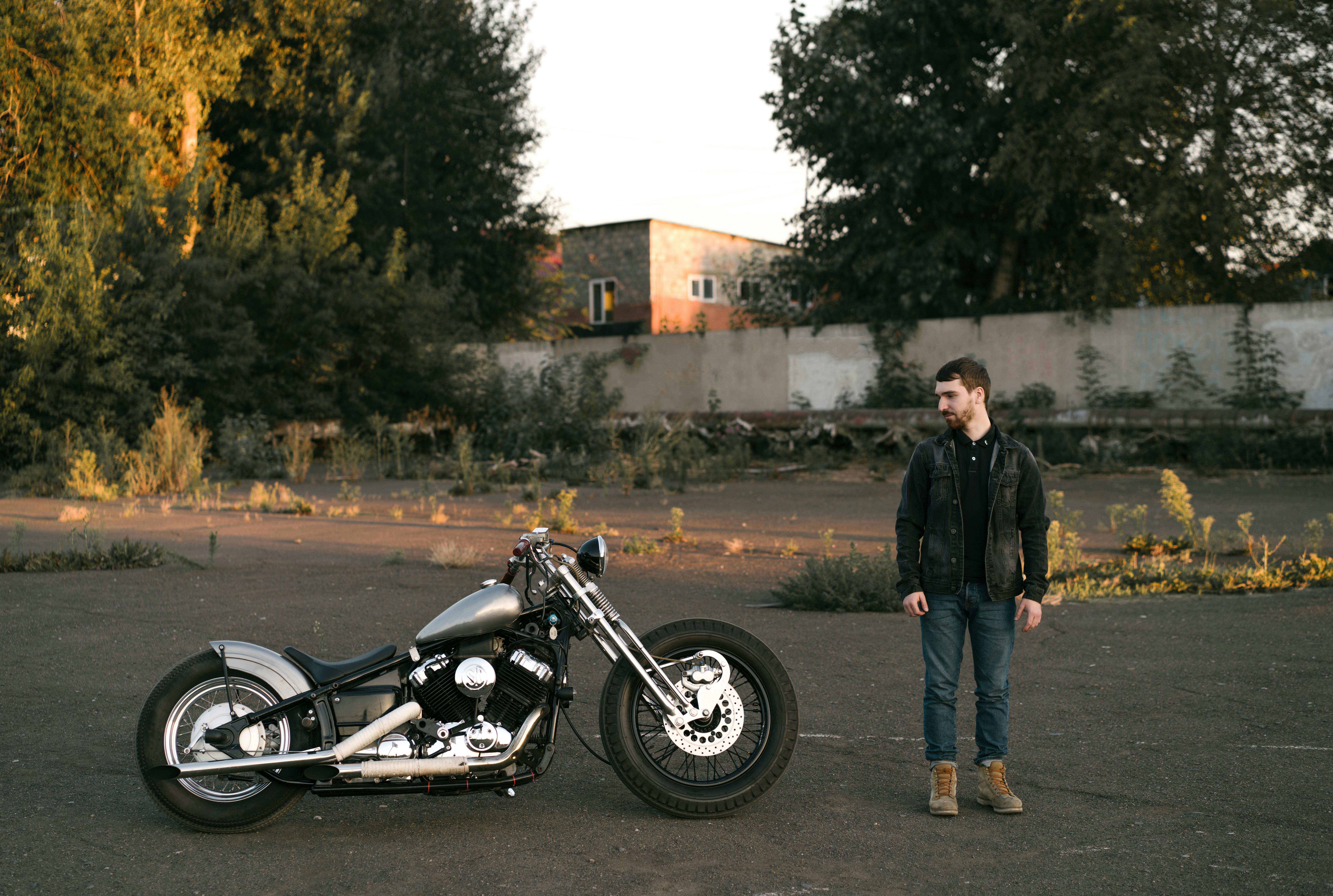 Man Standing next to and Looking at a Motorcycle · Free Stock Photo
