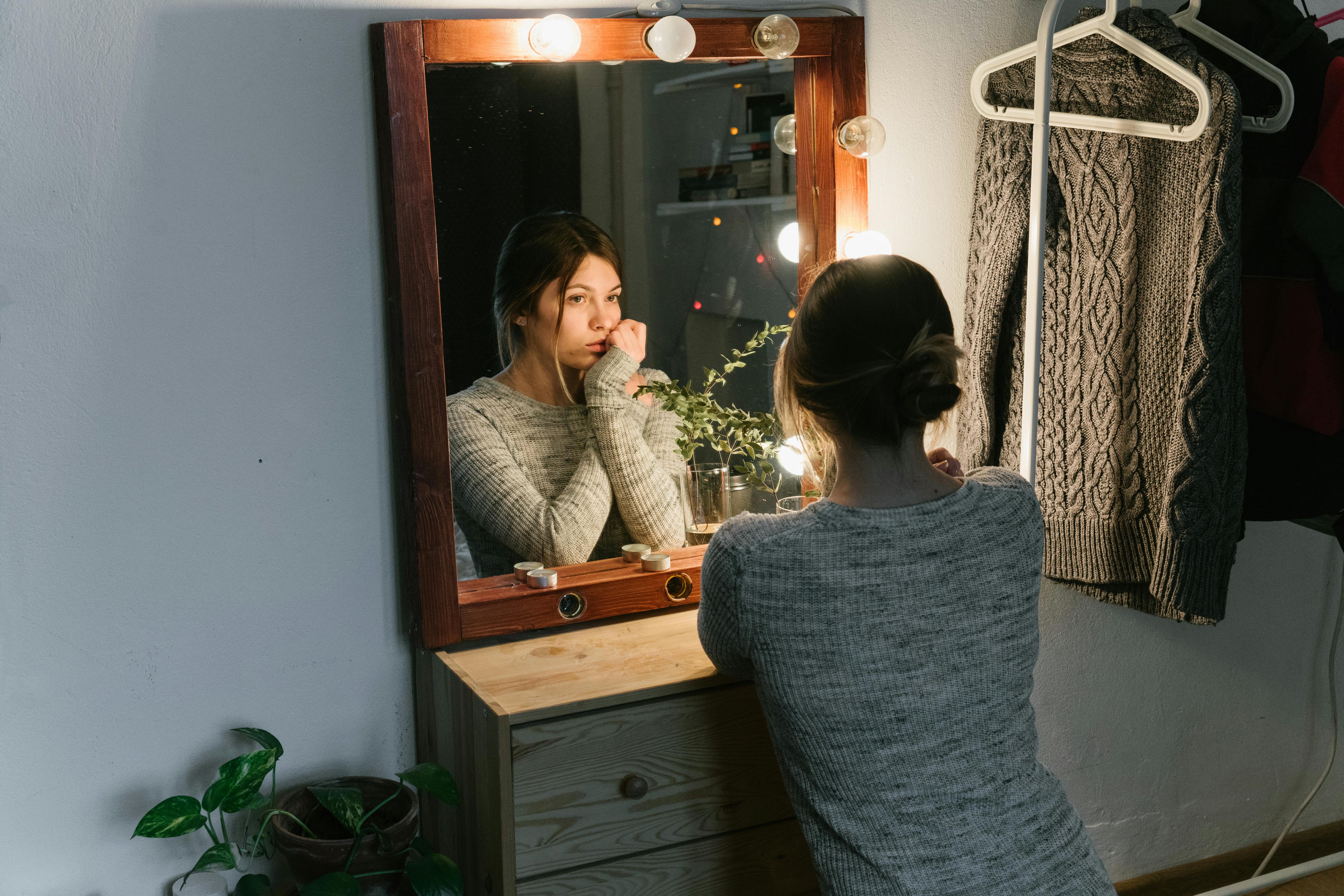 Woman in Gray Sweater Sitting in Front of a Mirror · Free Stock Photo