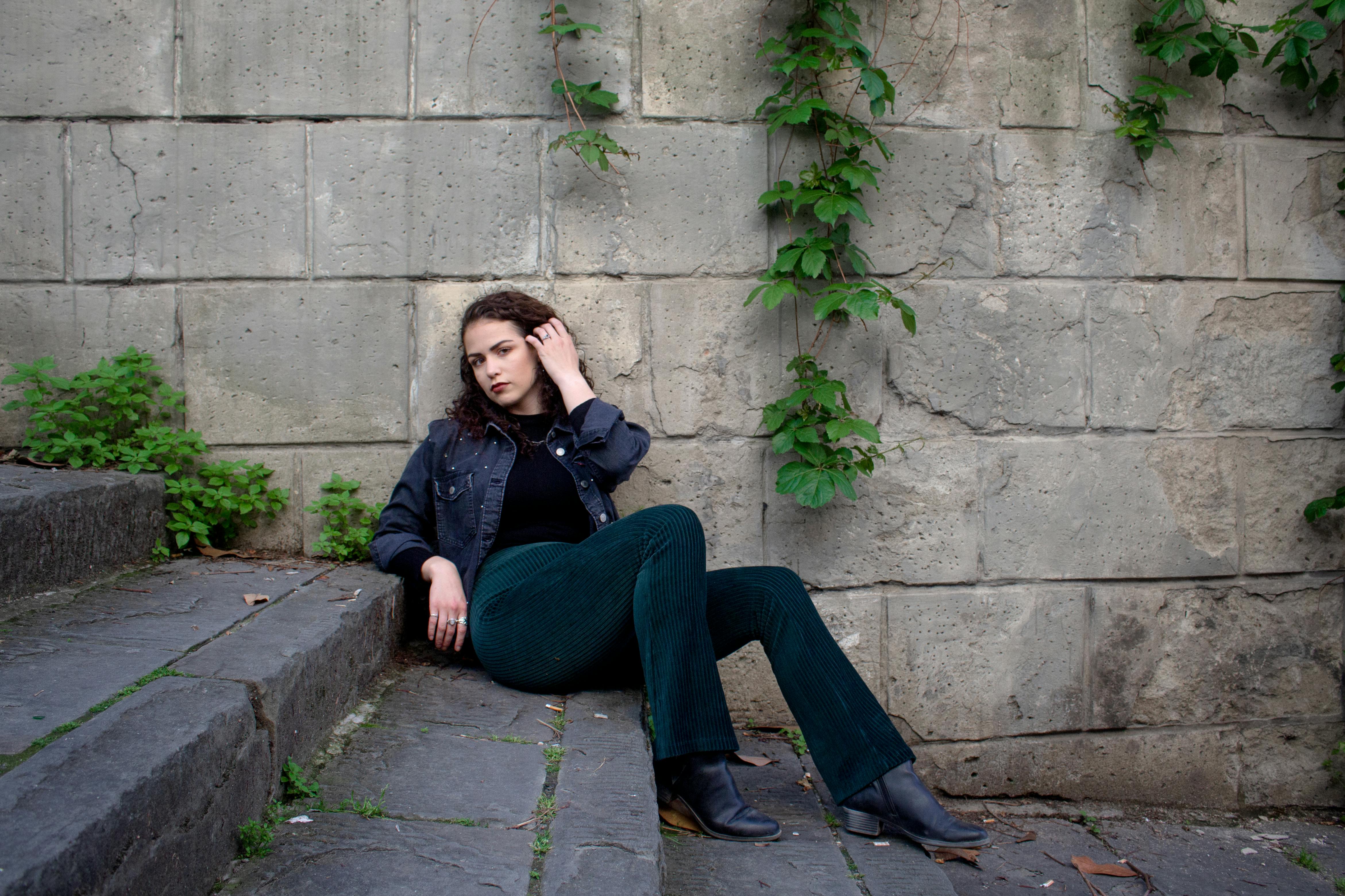 Young serious woman resting on stairs near shabby wall · Free Stock Photo