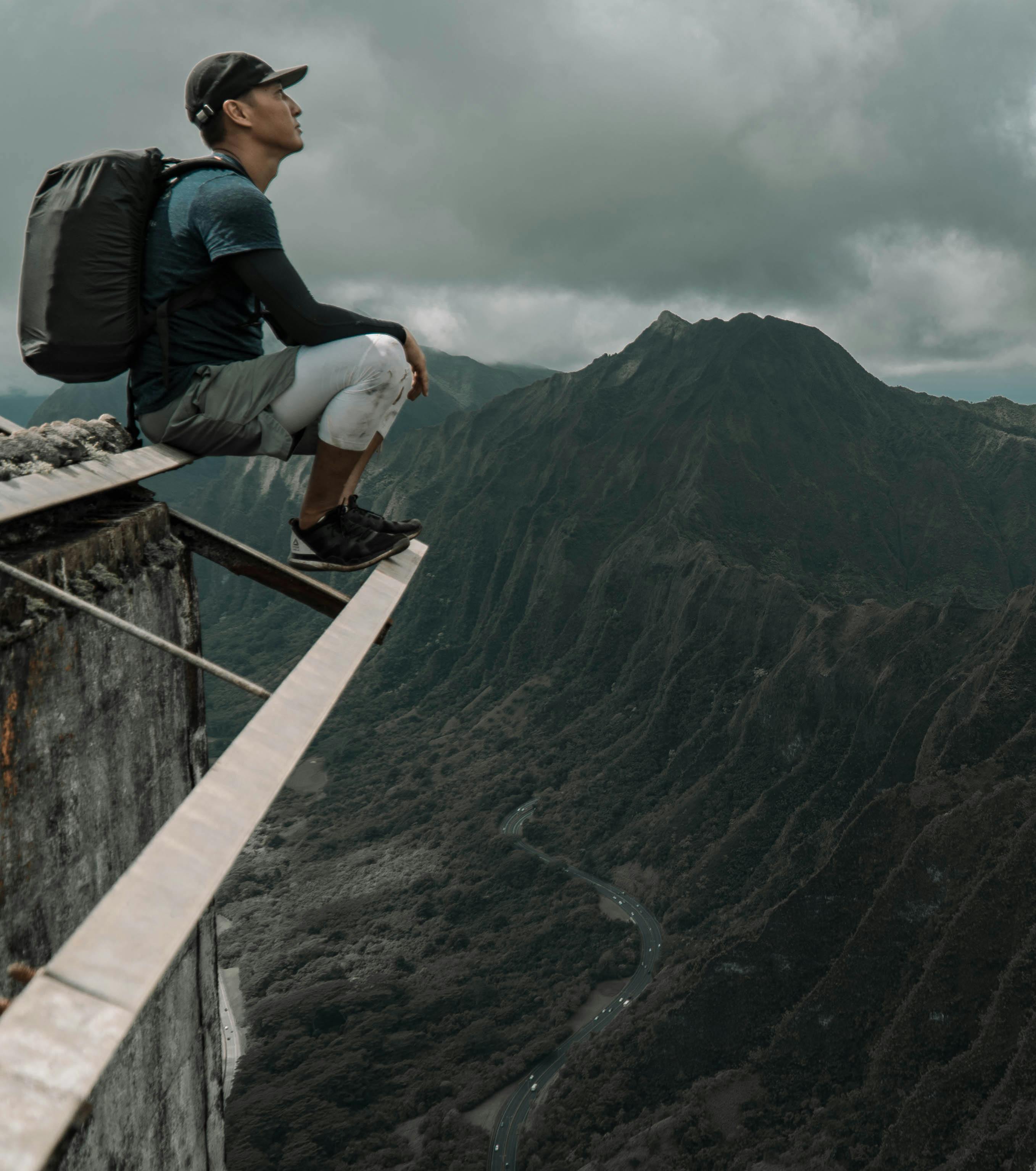 Man Sitting on High Railing in Mountains · Free Stock Photo