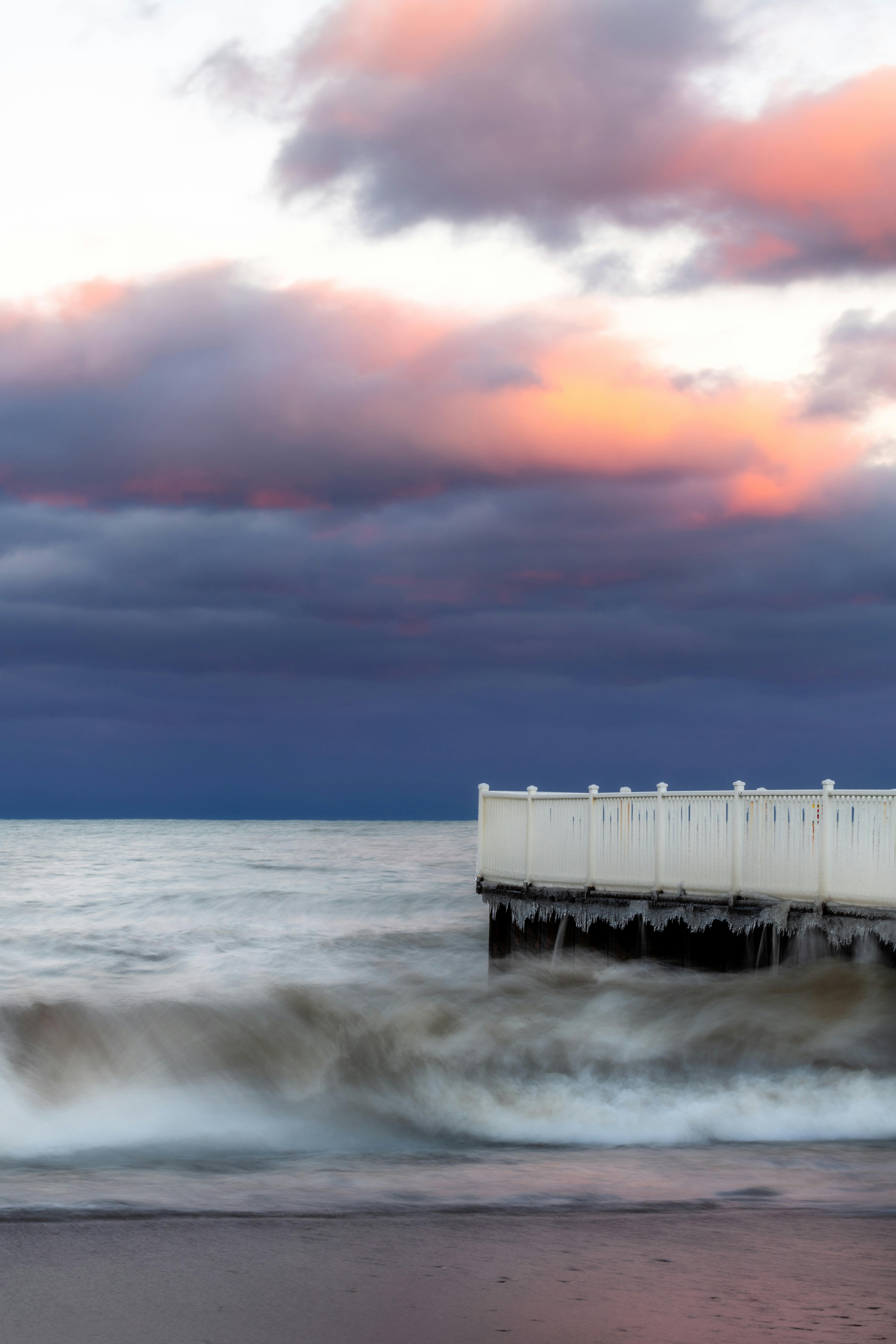 Pier on seashore under gray clouds · Free Stock Photo