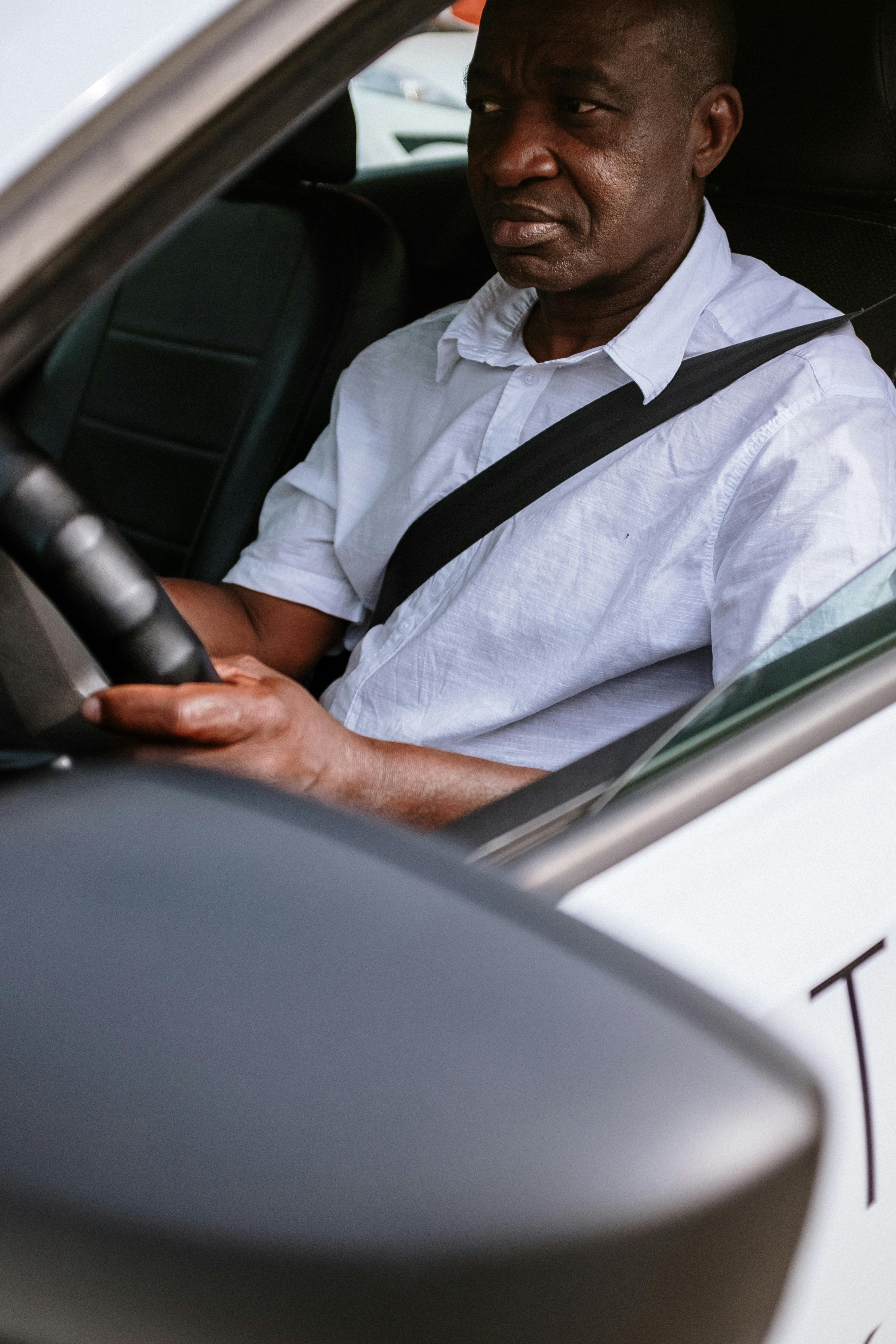 Attentive Asian male taxi driver in modern car · Free Stock Photo