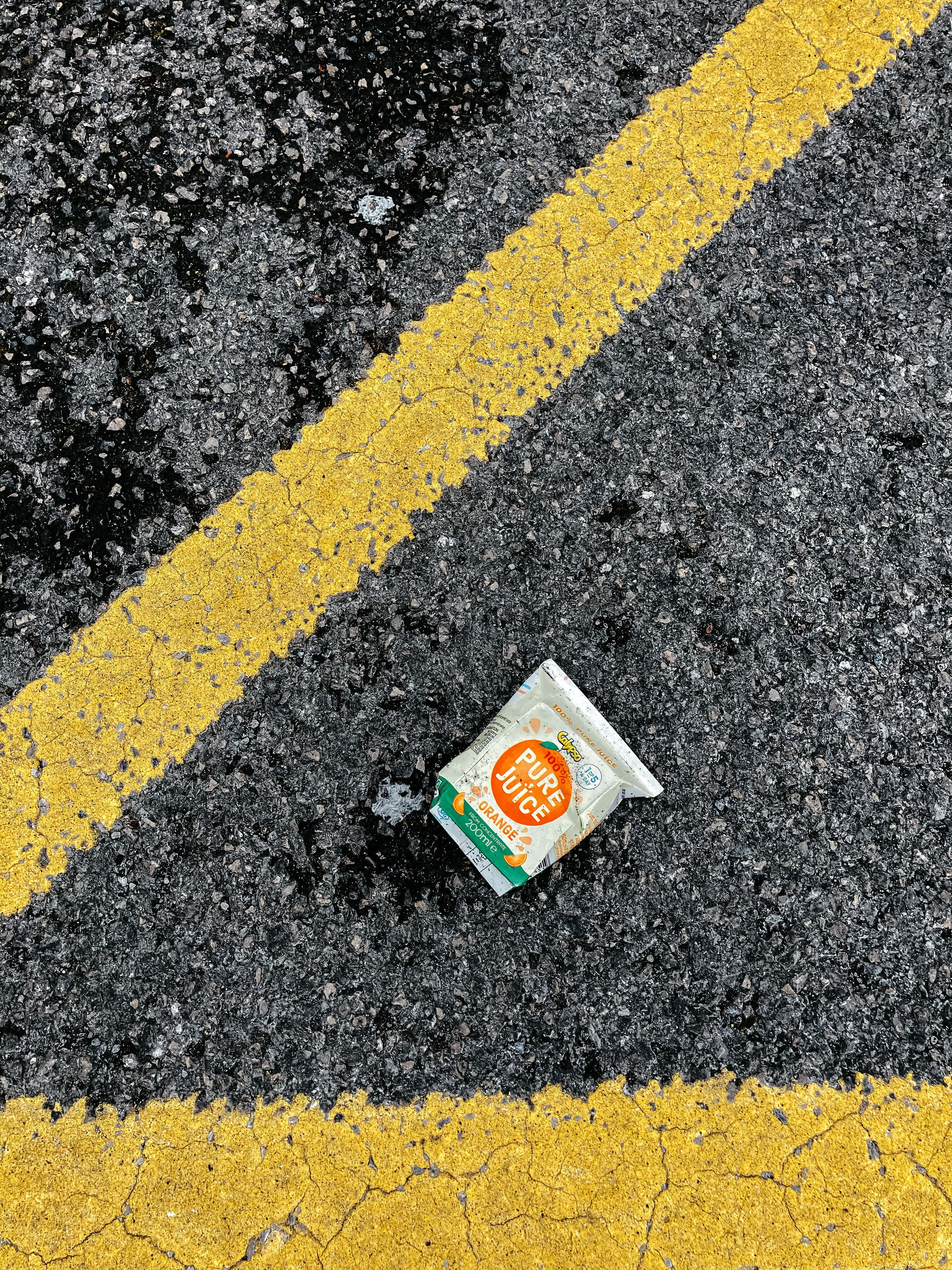Dumped Carton Box of Juice on Asphalt Road · Free Stock Photo