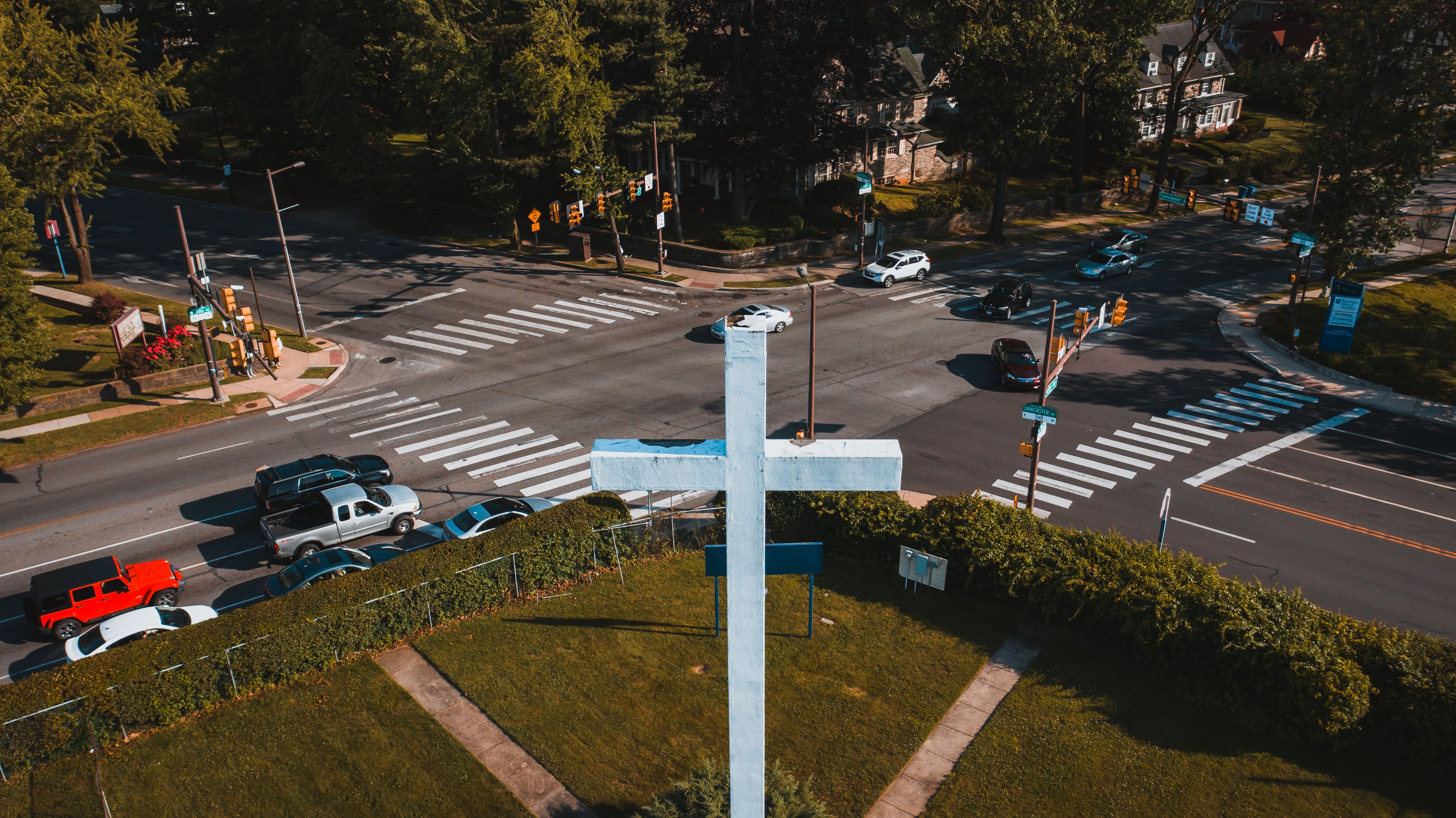 Old cross of church on lawn near city intersection · Free Stock Photo