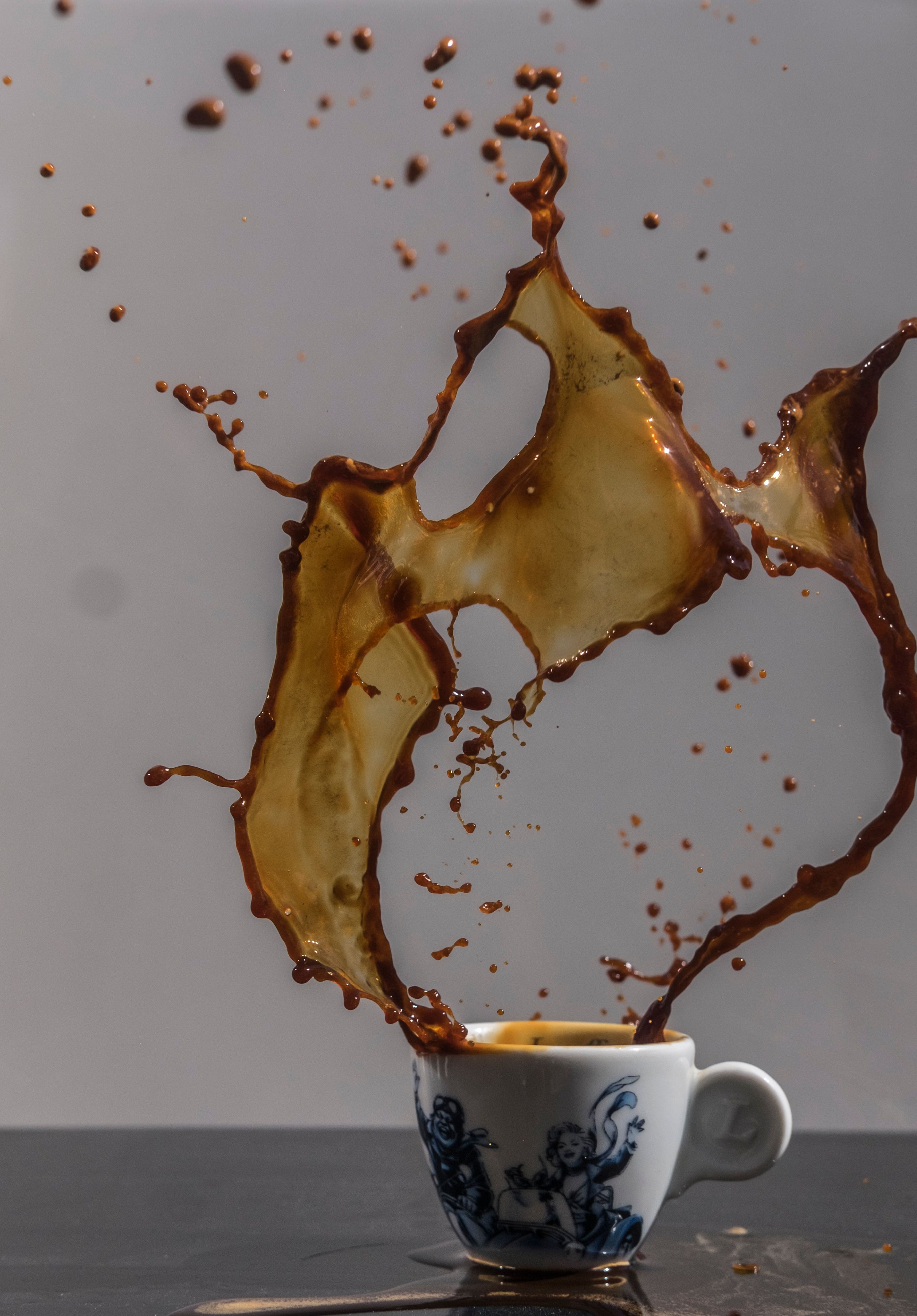 Ornamental cup with fast coffee flow in air · Free Stock Photo