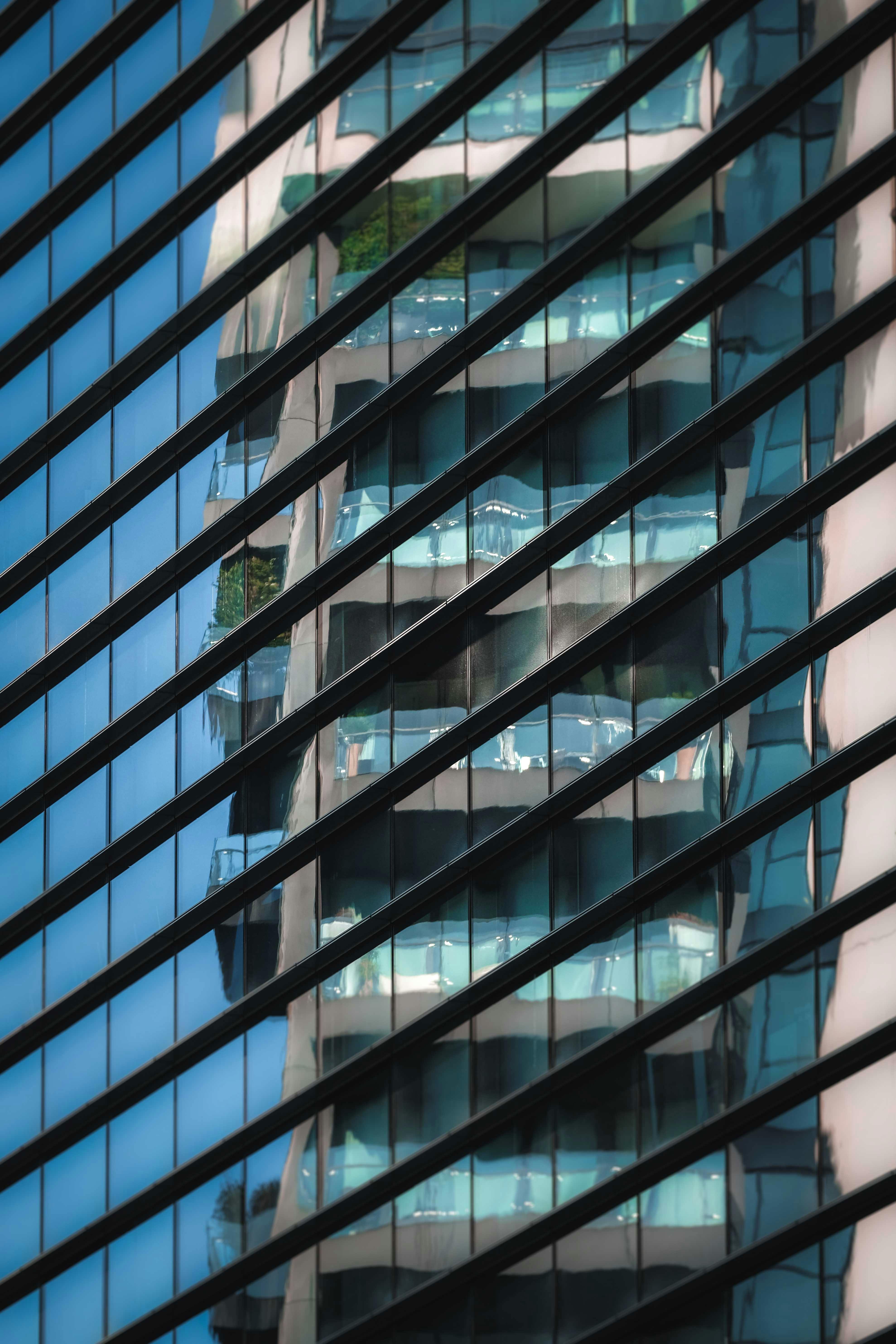 Modern glass building wall reflecting urban skyscraper · Free Stock Photo