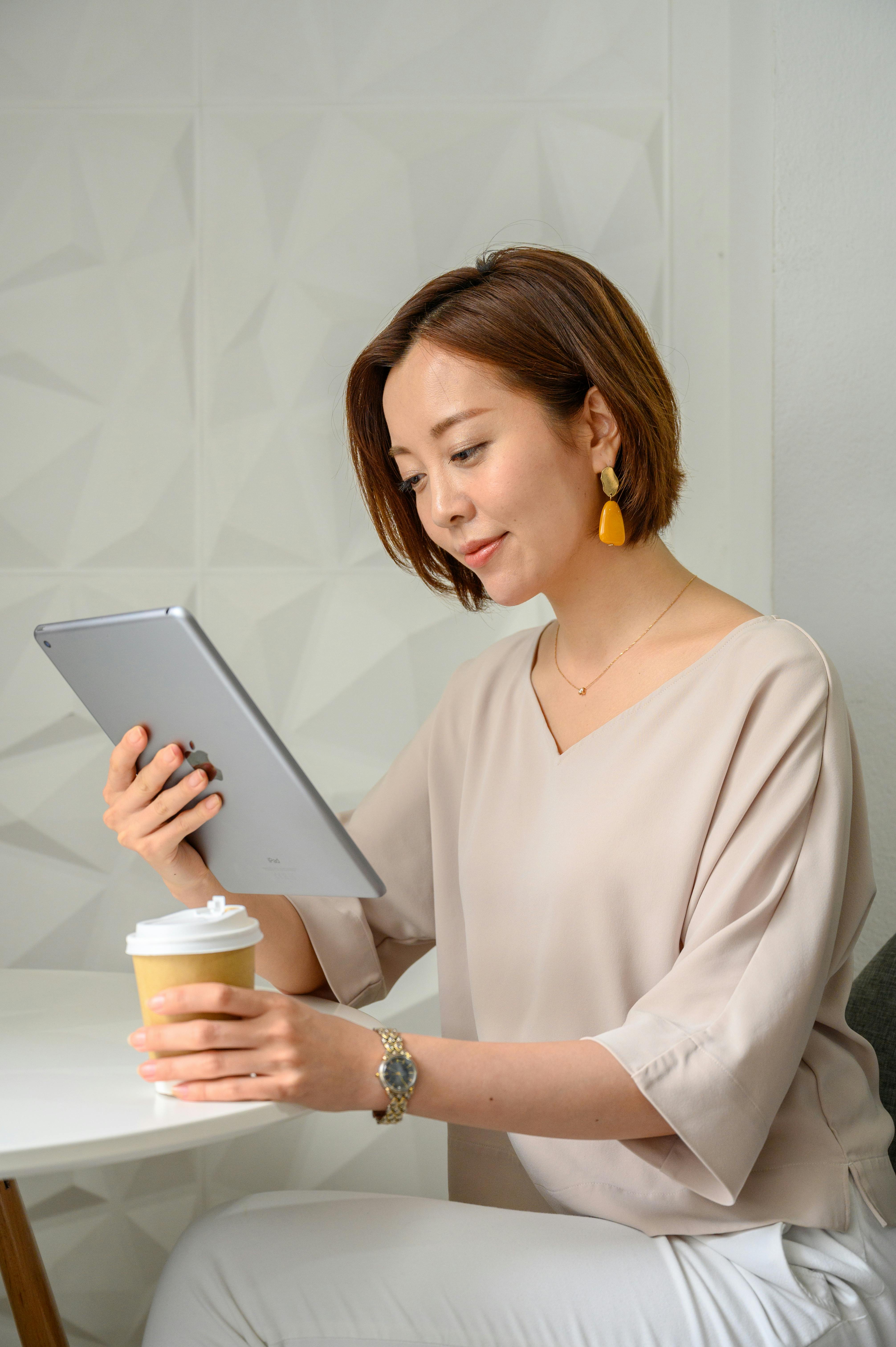 Woman Using Tablet and Drinking Coffee from a Disposable Cup · Free ...