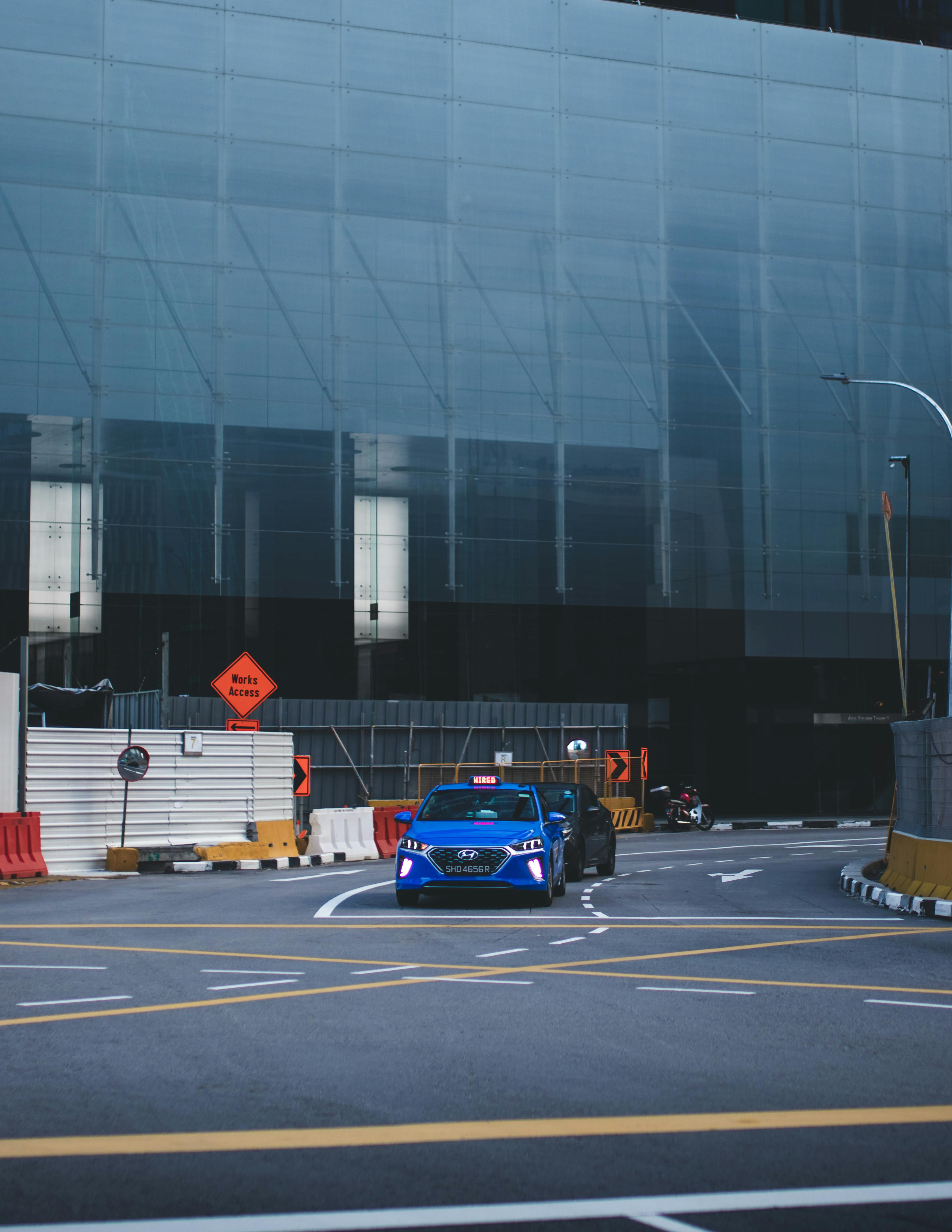 Modern vehicles driving on road near glass building · Free Stock Photo