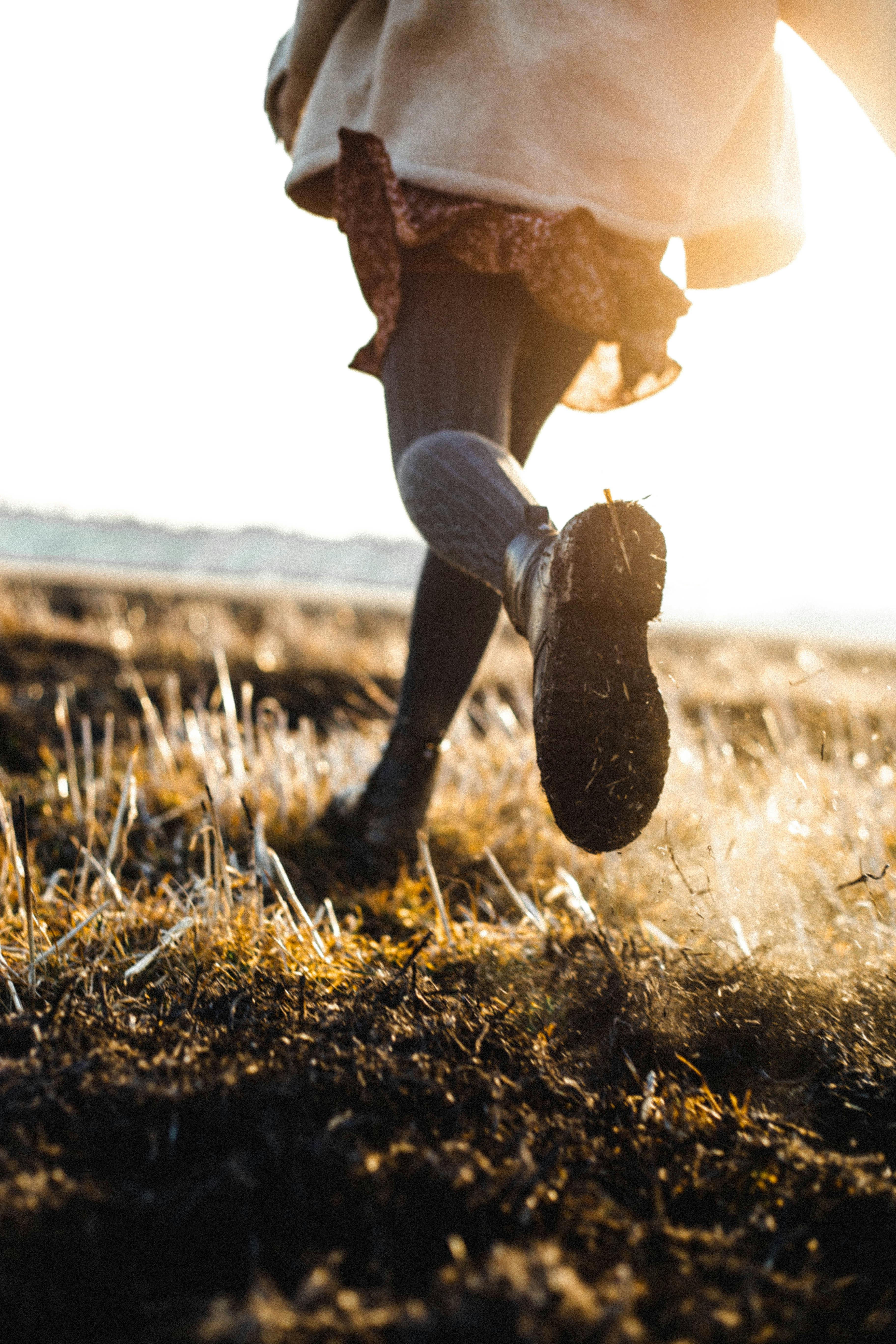 Person Wearing Black Boots Running on Brown Grass · Free Stock Photo