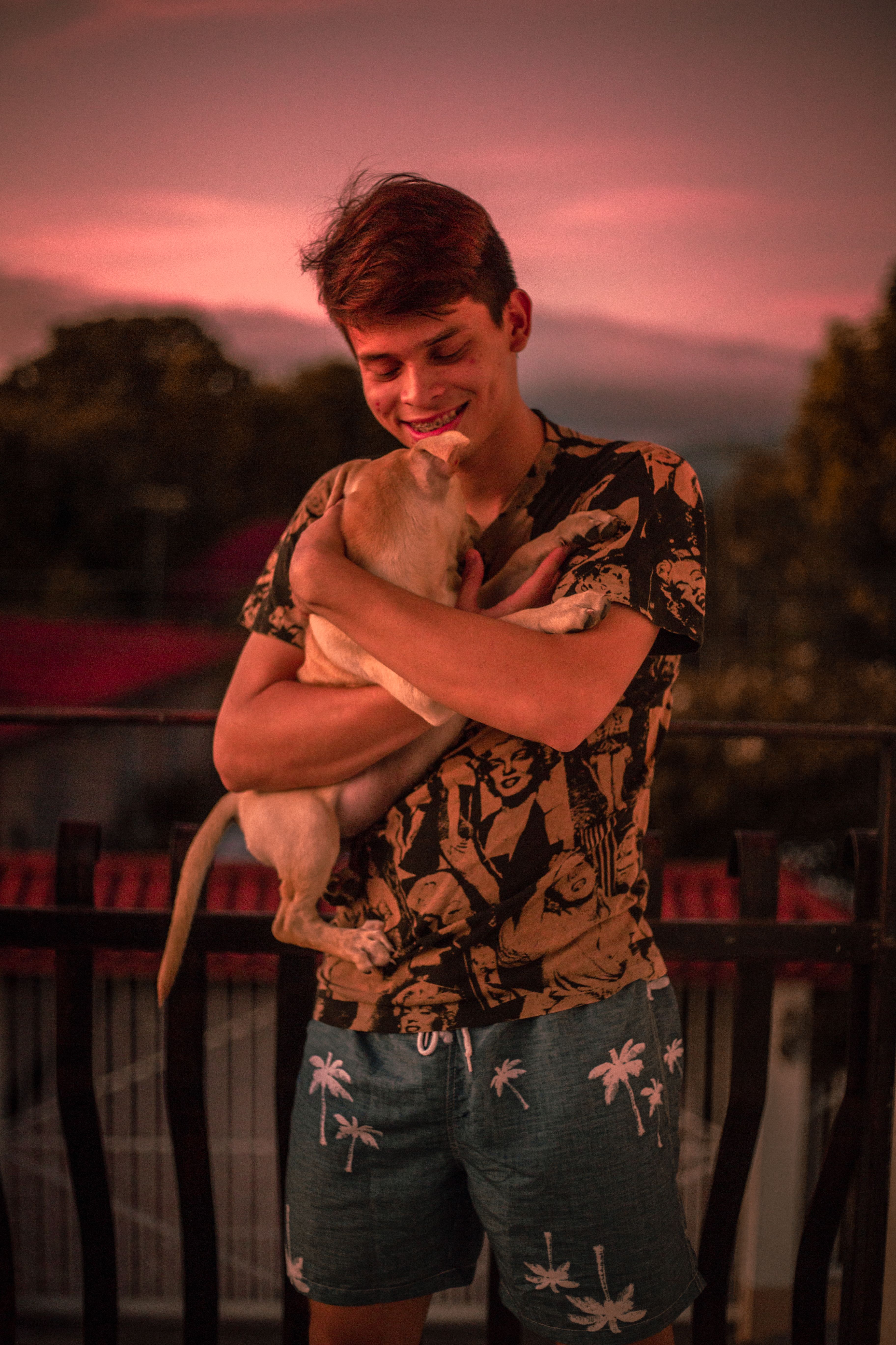 A Man Standing While Carrying a Brown Dog · Free Stock Photo