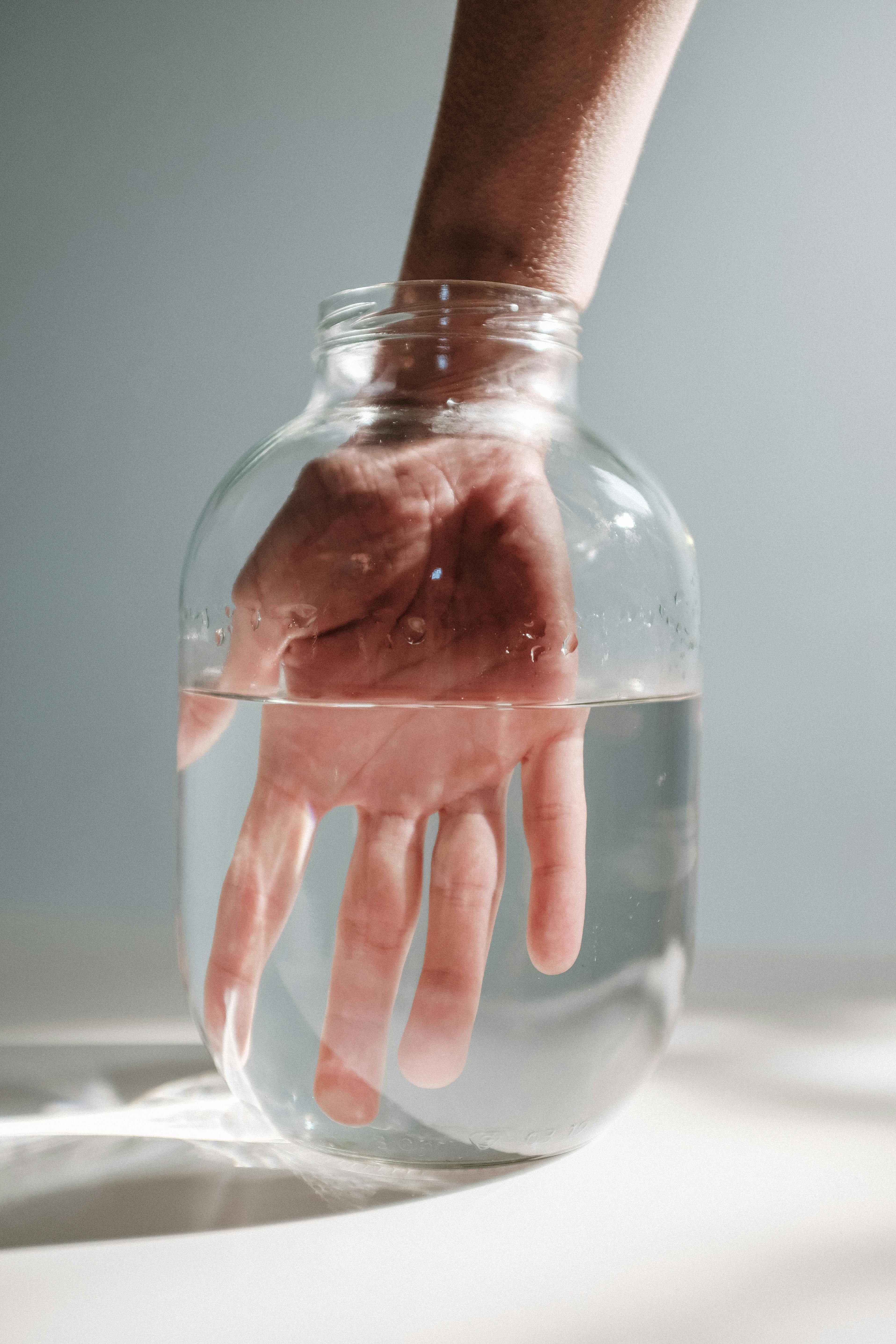 Hand Of A Person Inside A Clear Glass Jar With Water · Free Stock Photo