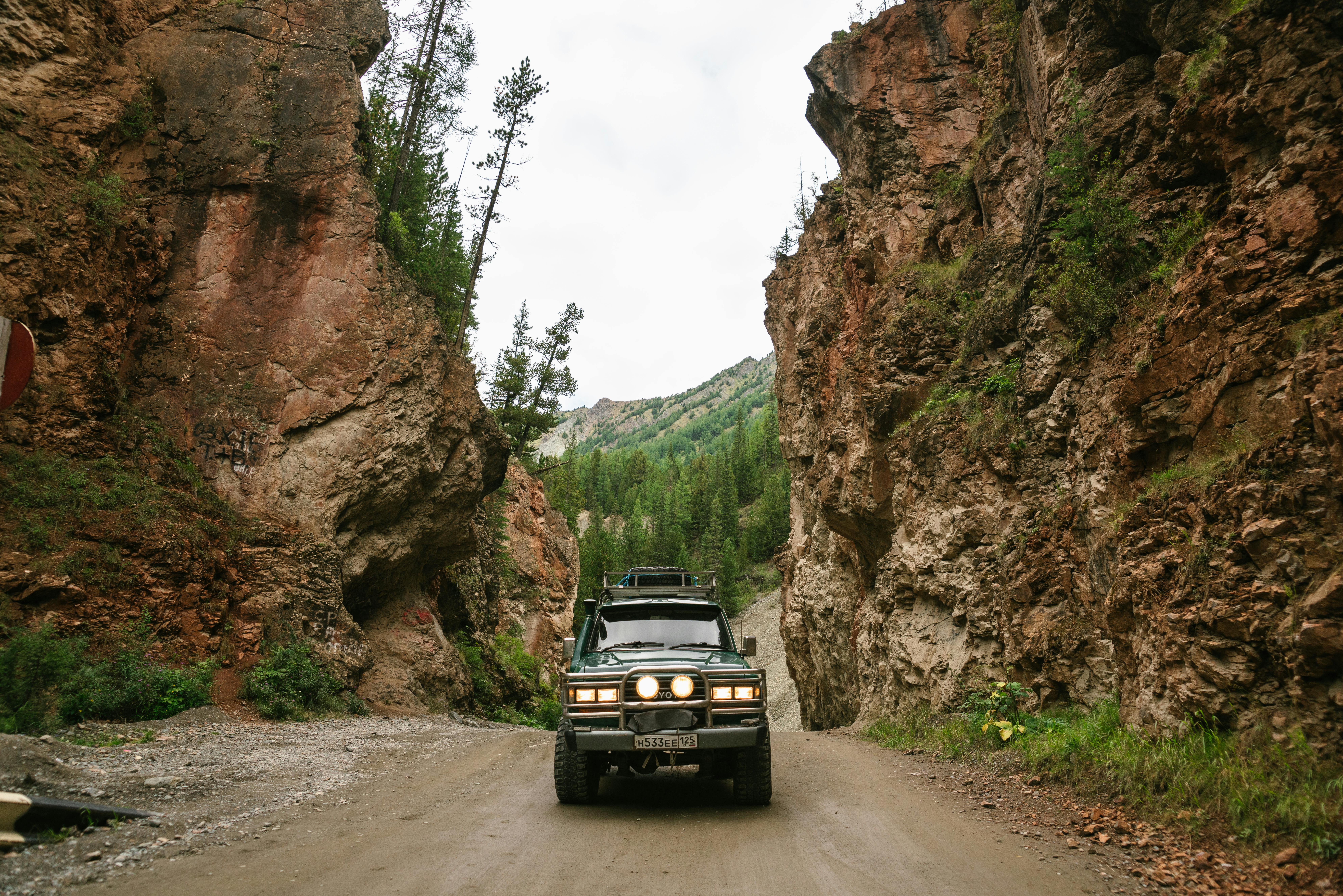 Black Suv Moving on the Road Between Big Rock Formations · Free Stock Photo