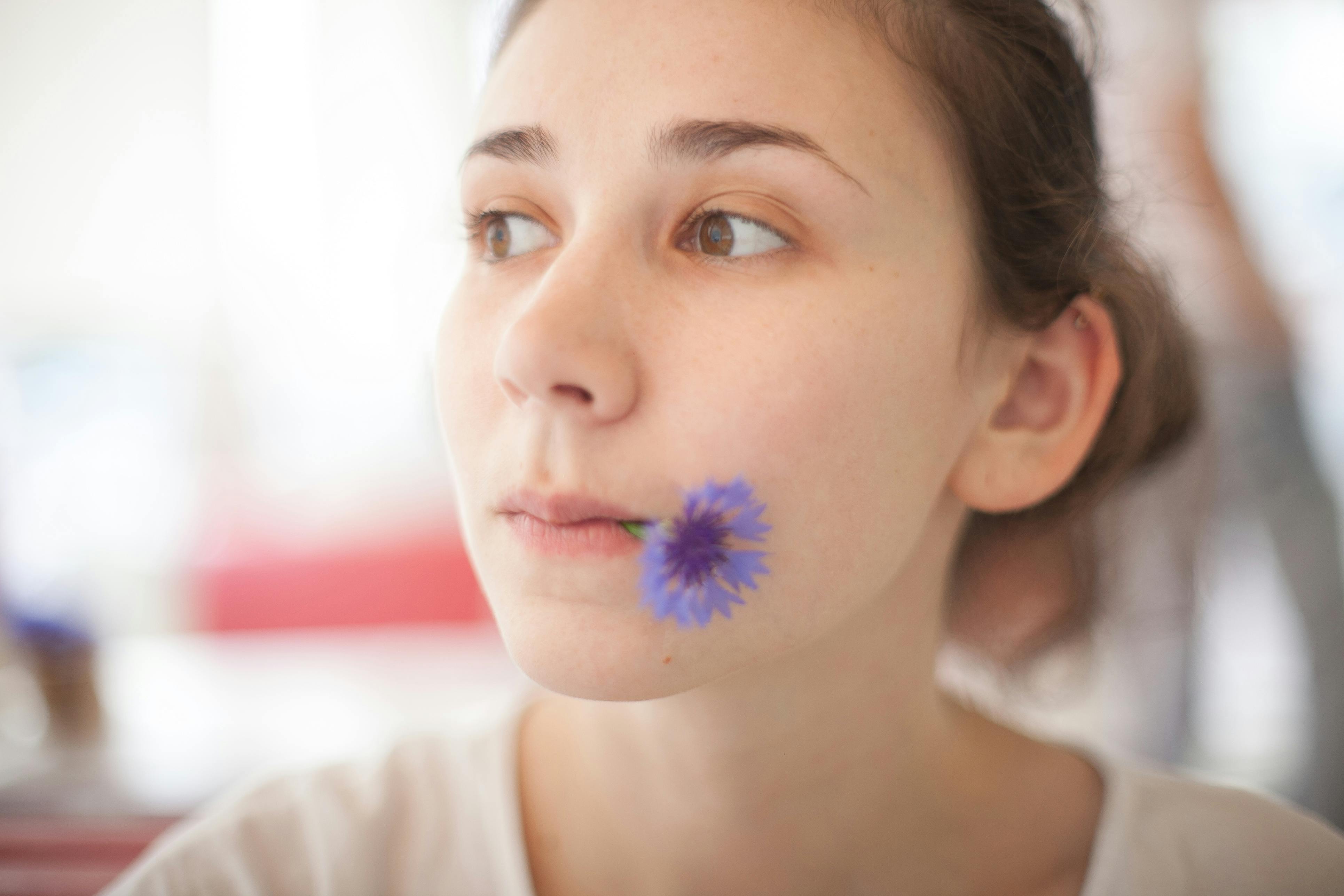 Portrait Photo of Woman Biting Blue Flower · Free Stock Photo