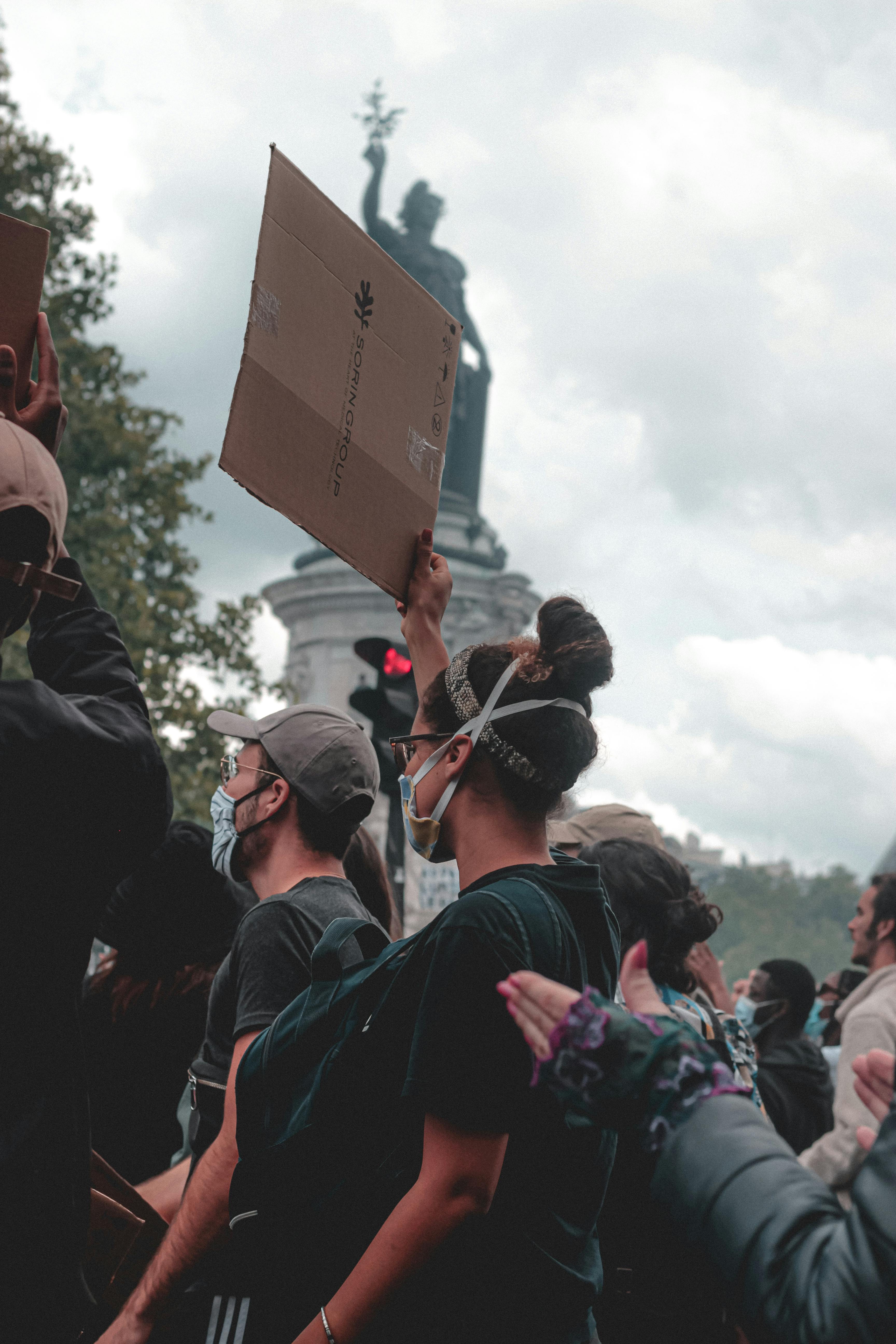 Protesting people in masks near monument · Free Stock Photo