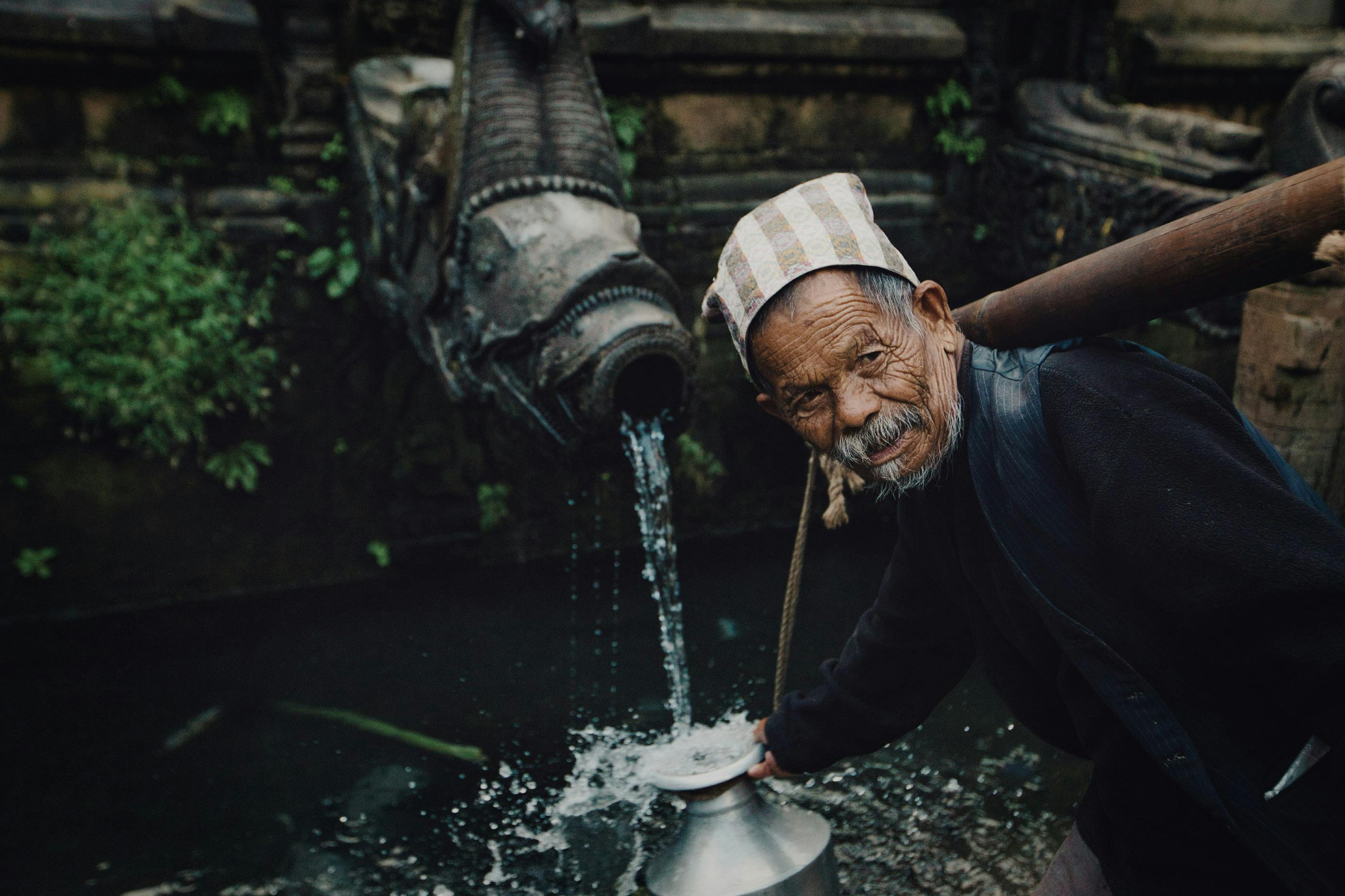 Man Pouring a Metal Bucket of Water · Free Stock Photo
