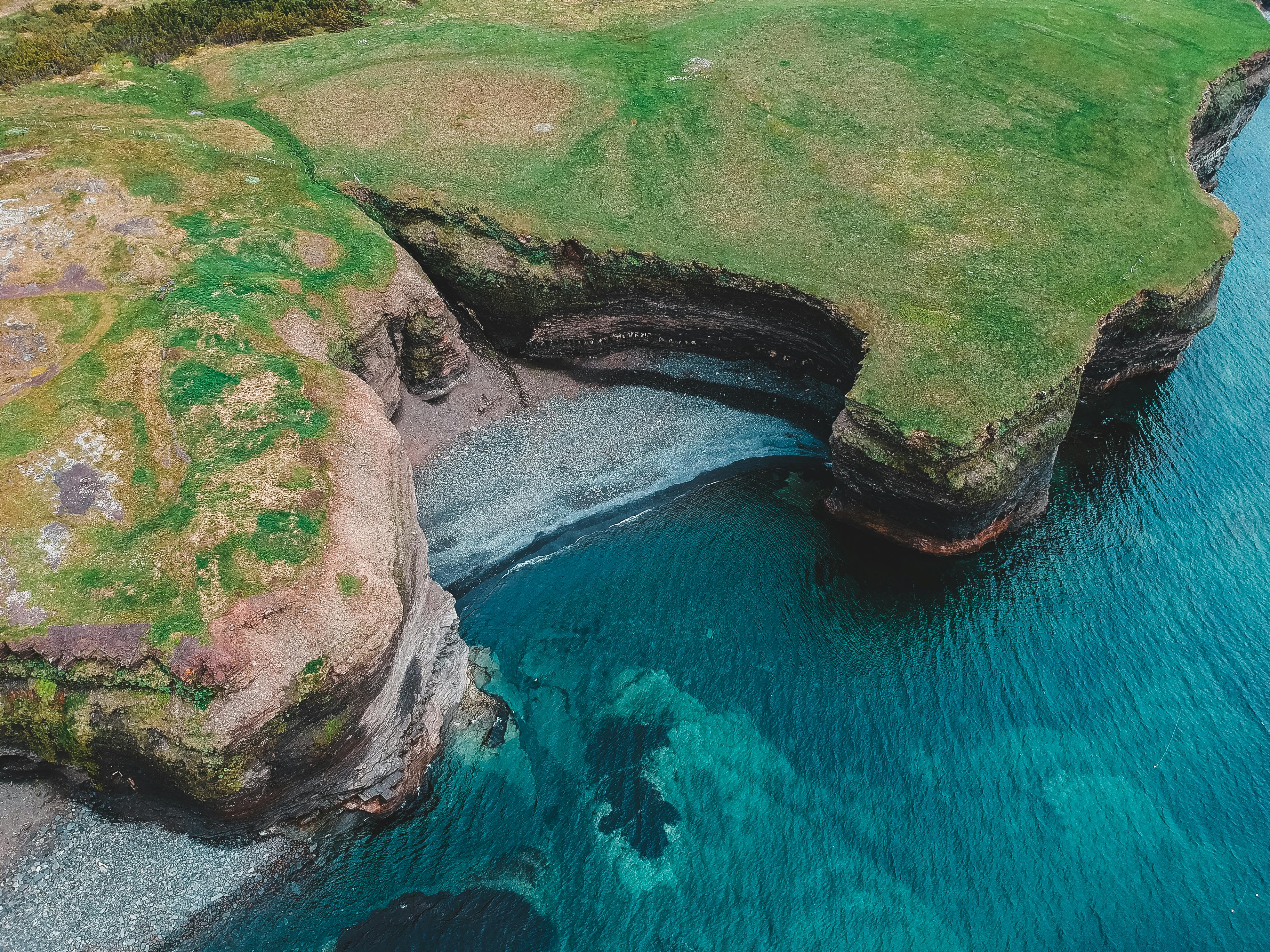 High cliffs with colorful grass on even top near turquoise bay · Free ...