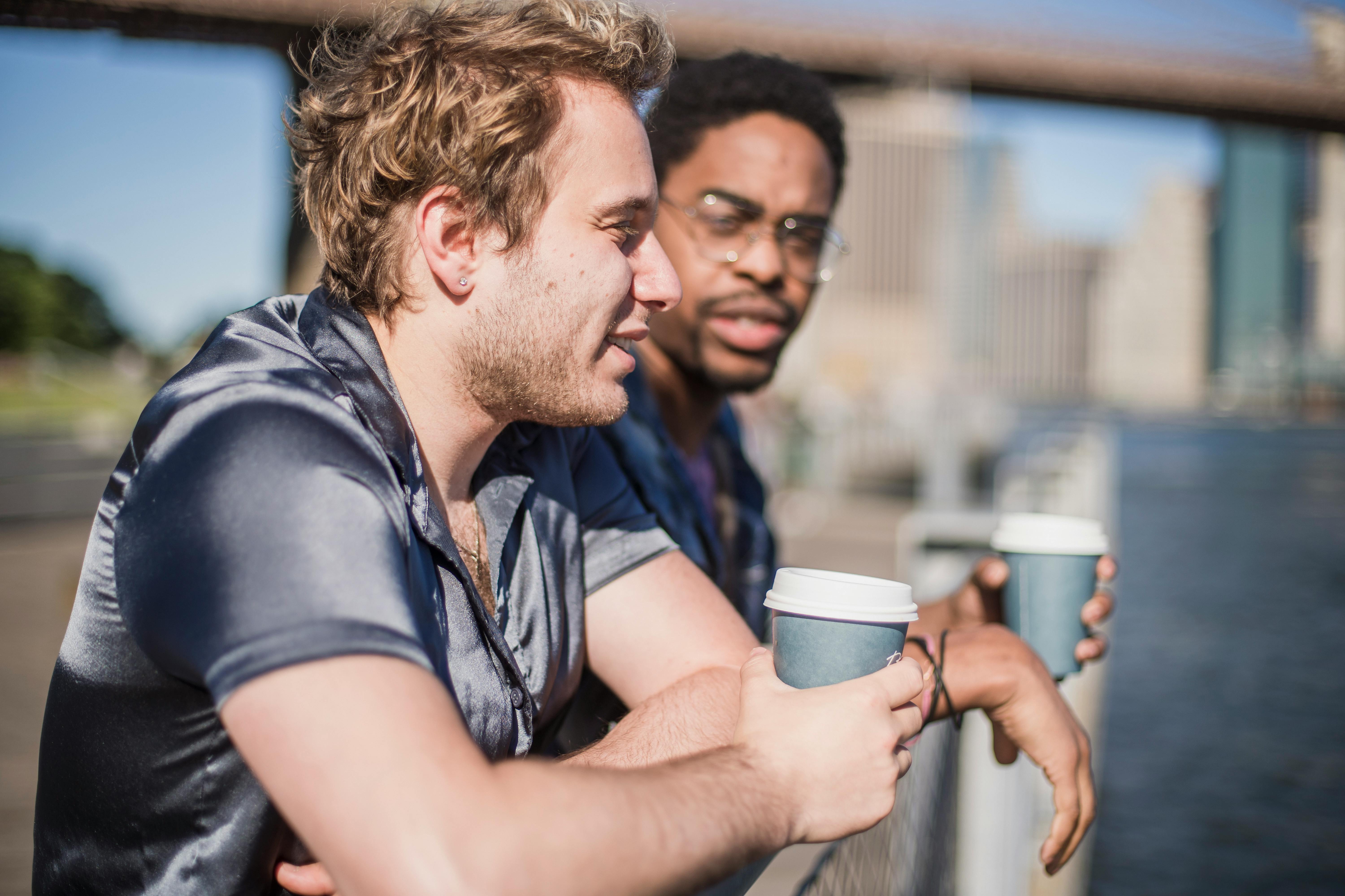 Two Men Having Coffee and Leaning on Railing · Free Stock Photo