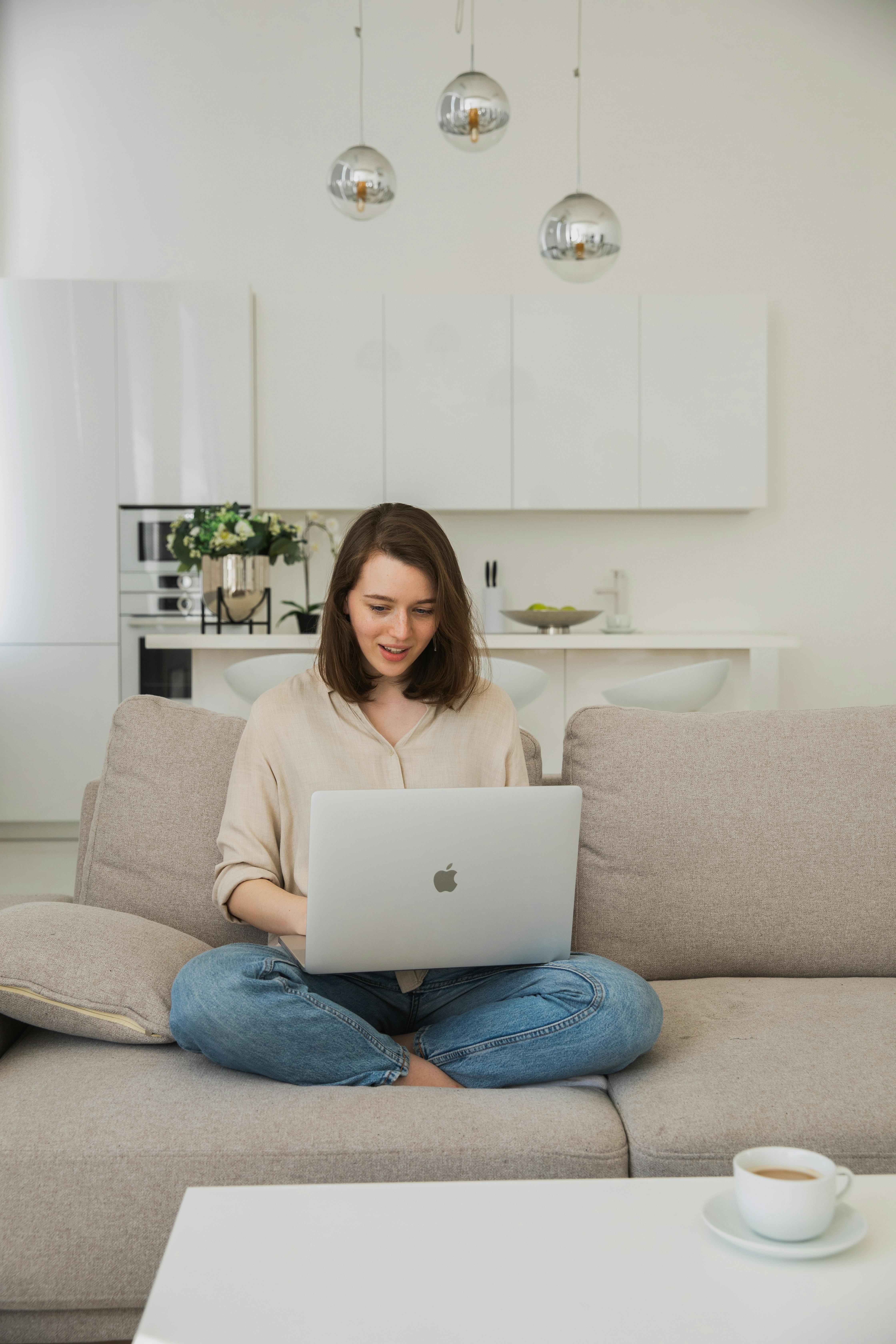 Young Woman Sitting on a Sofa Using a Laptop · Free Stock Photo