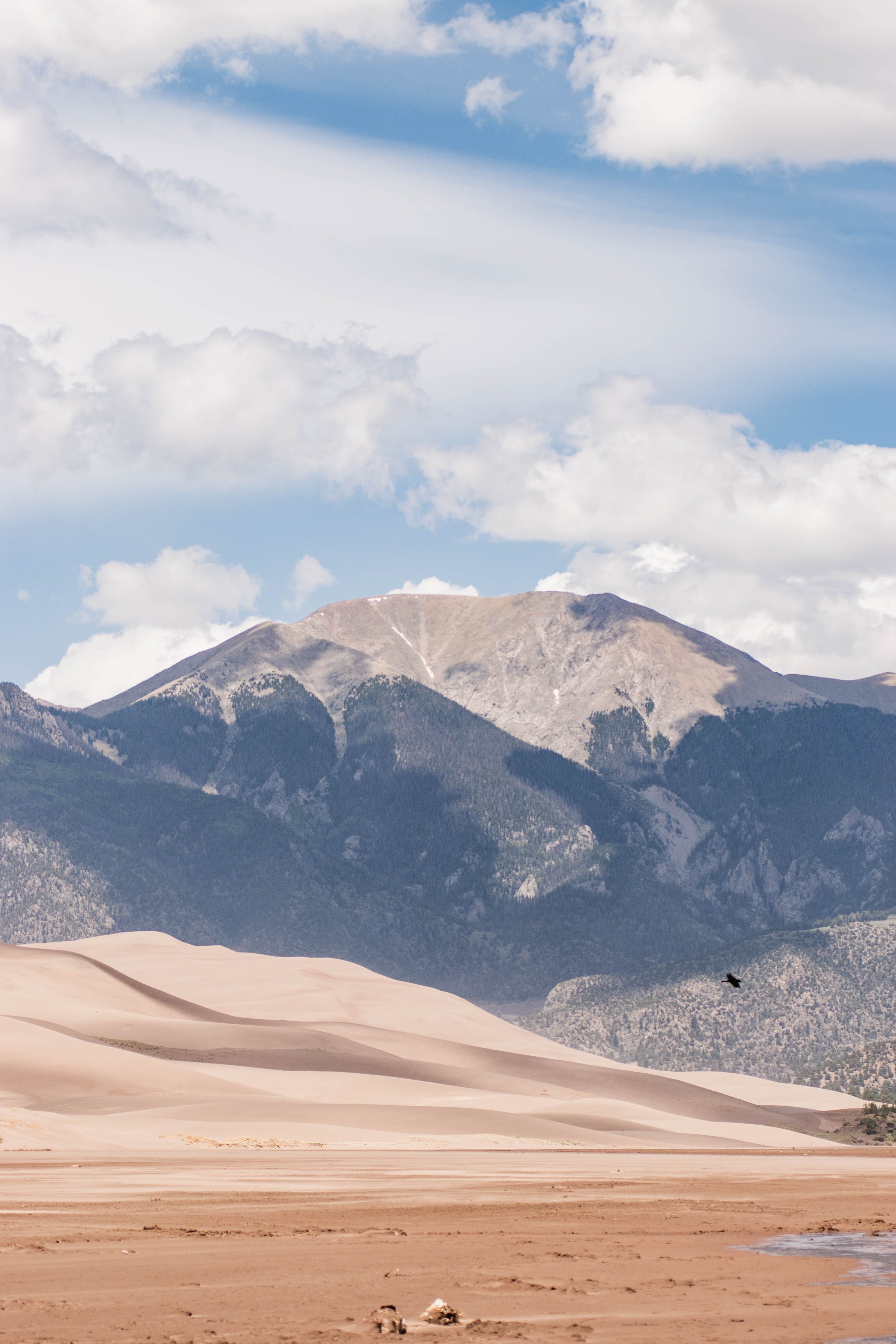 Sand Dunes and Mountains Under White Clouds and Blue Sky · Free Stock Photo