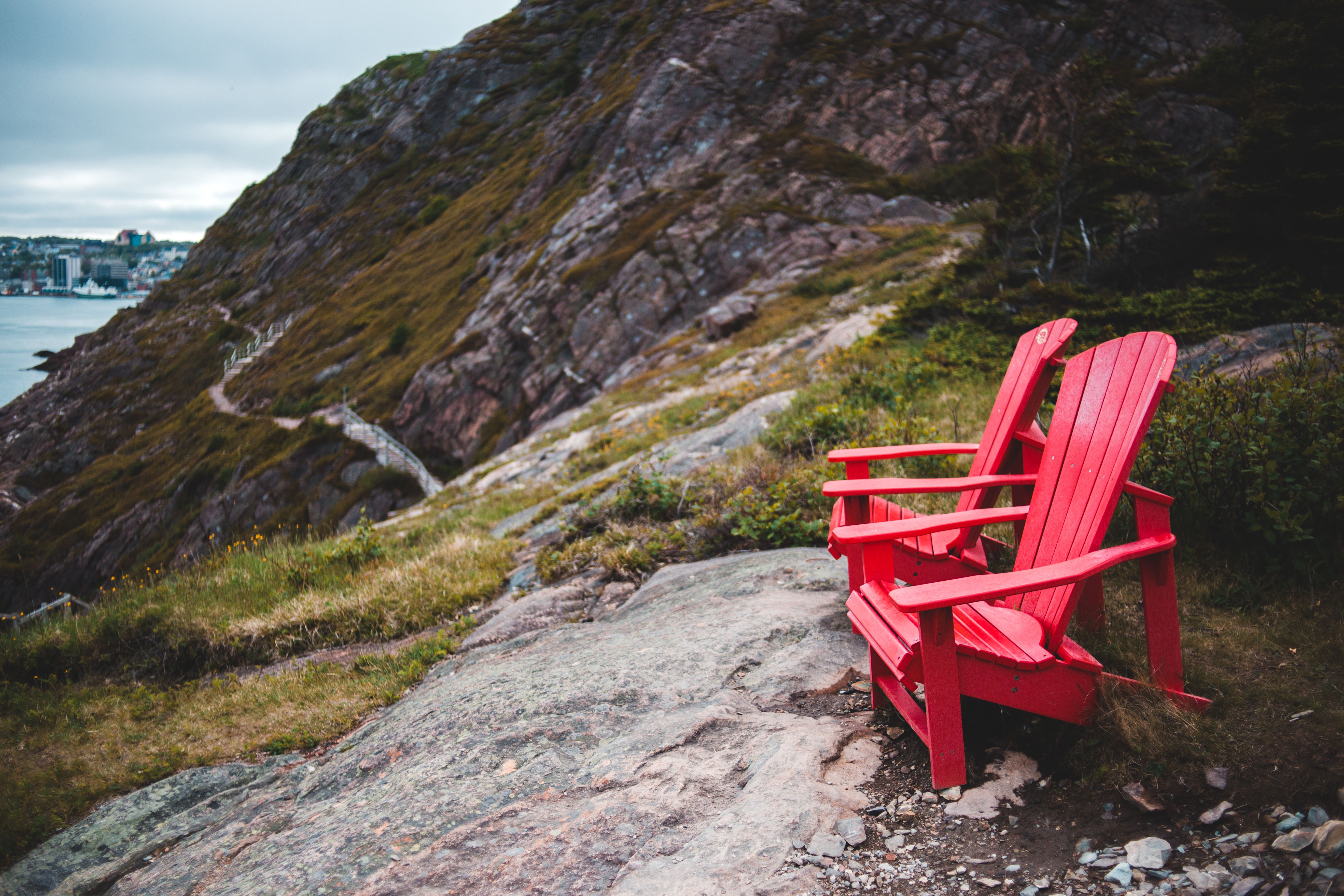 Plastic chairs on rocky green coast · Free Stock Photo