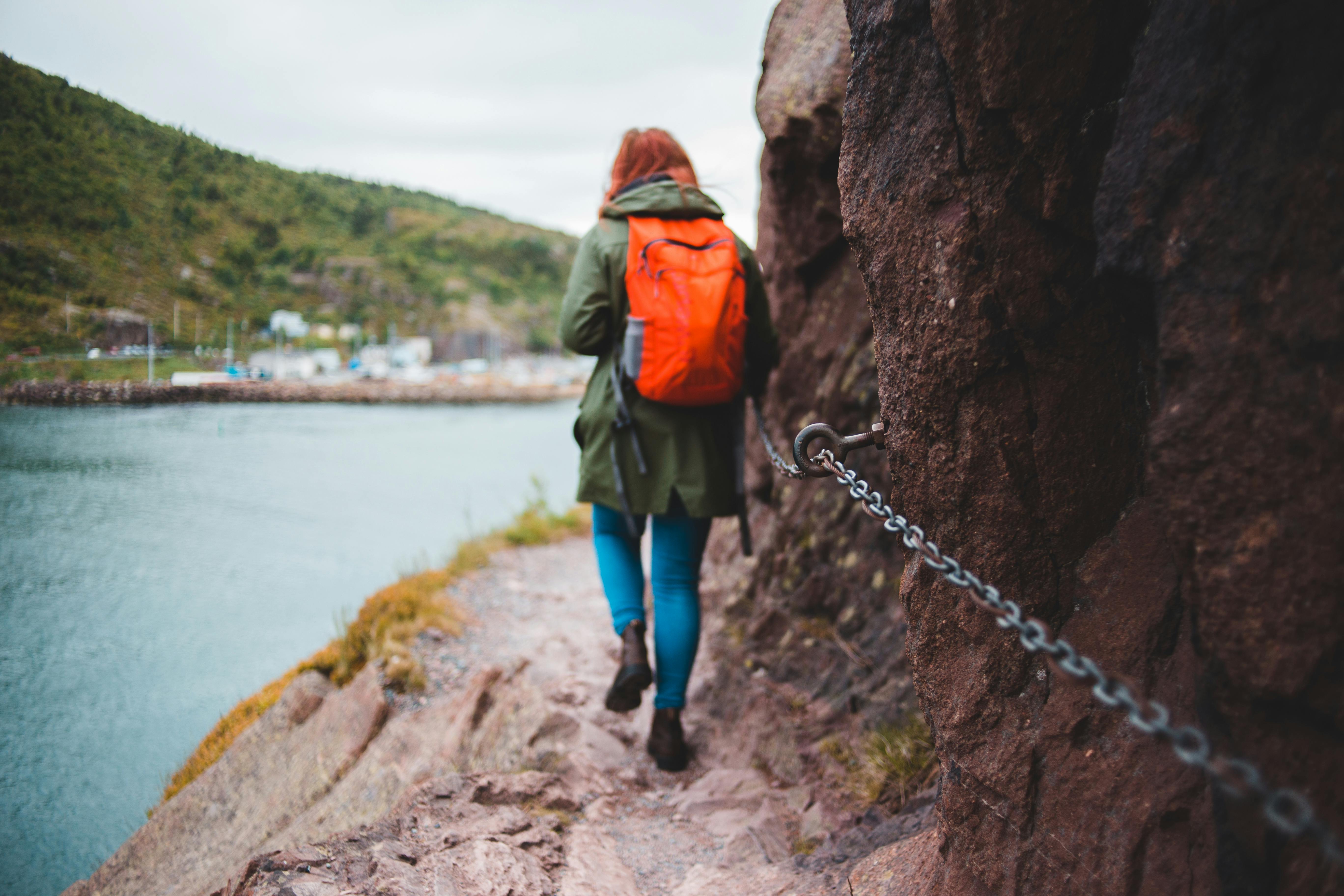 Woman walking on rocky cliff decorated with chain · Free Stock Photo