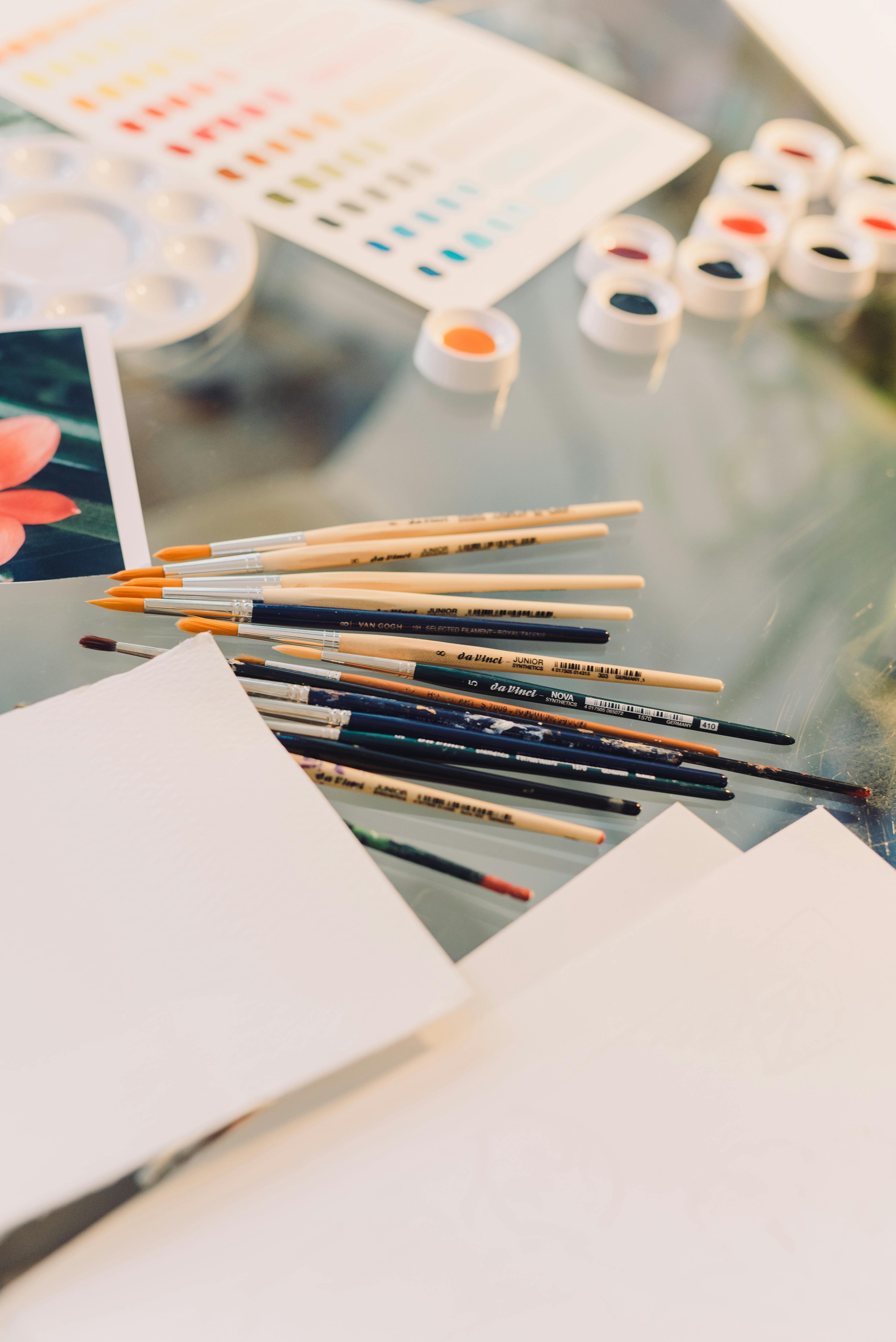 Brushes by Papers on Glass Table · Free Stock Photo