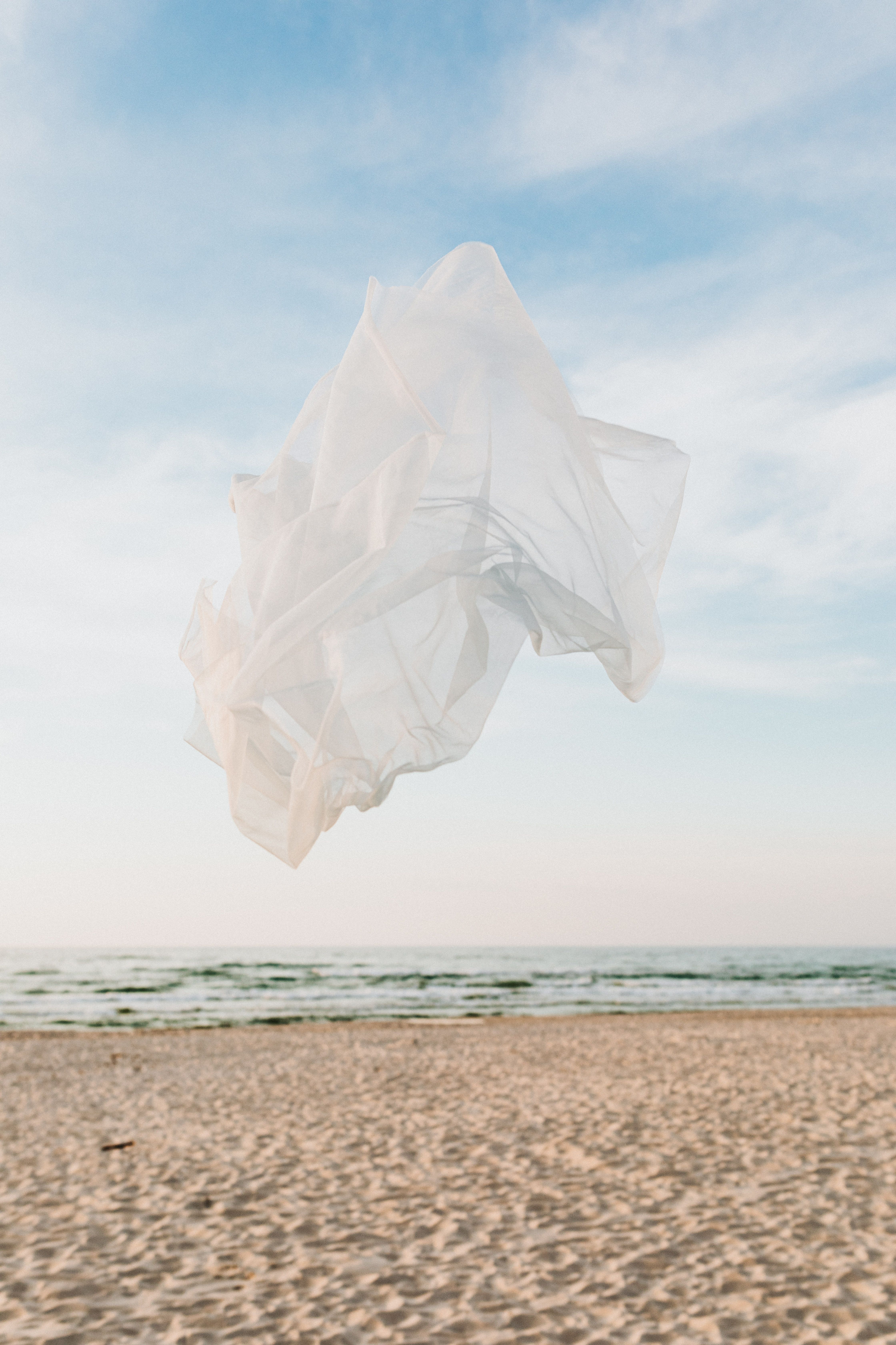 Wind Blowing on White Sheer Fabric Over Beach Shore · Free Stock Photo