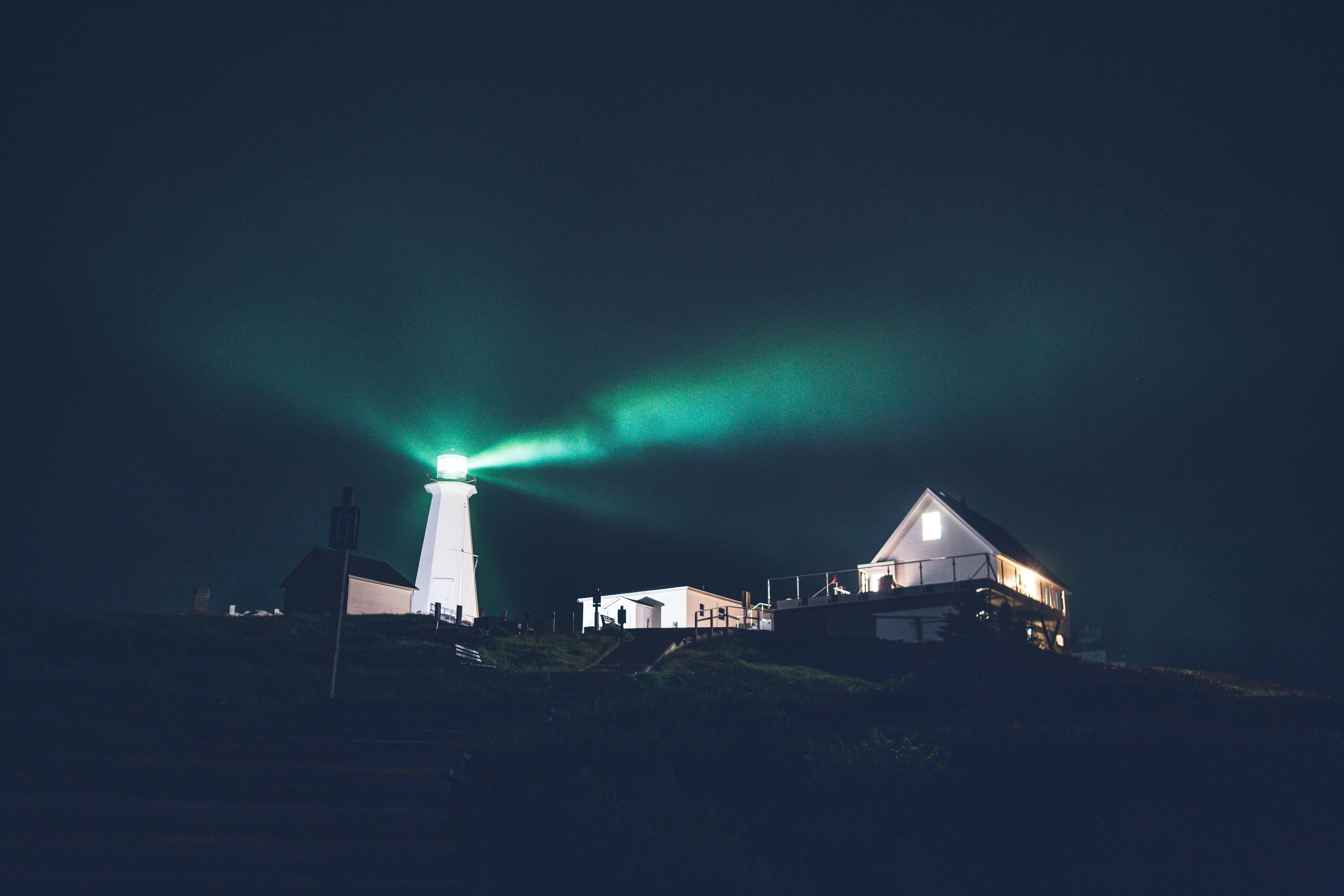 Green lighthouse in dark night on hill · Free Stock Photo