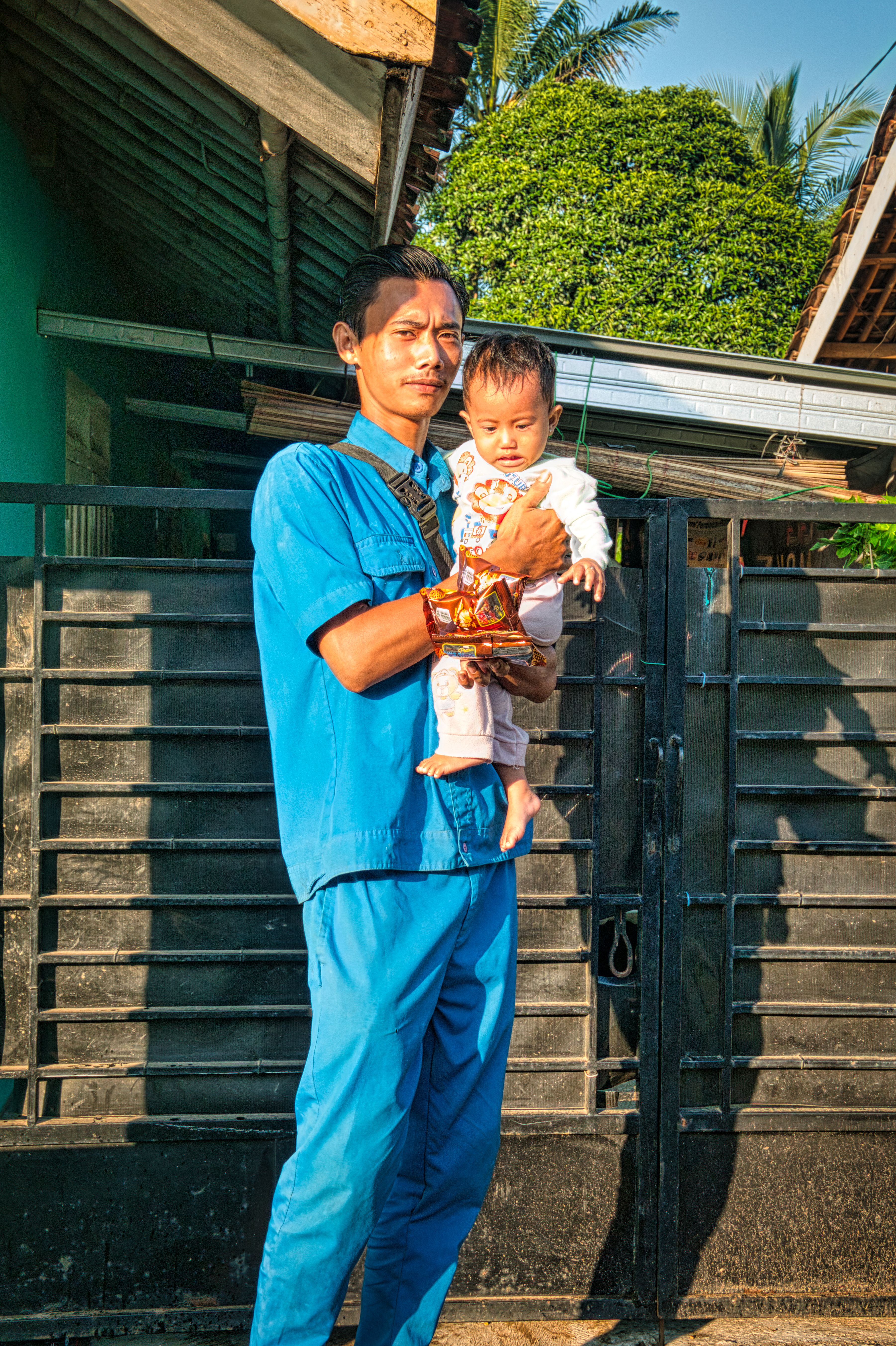 Man Carrying a Boy Near a Metal Gate · Free Stock Photo