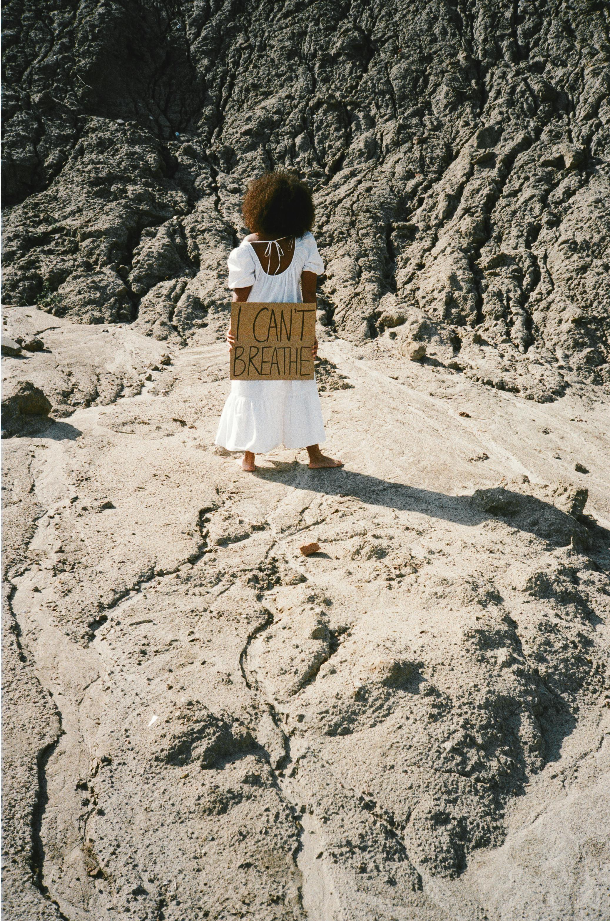 Woman Standing in the Desert and Holding a Cardboard Sign with a Slogan ...