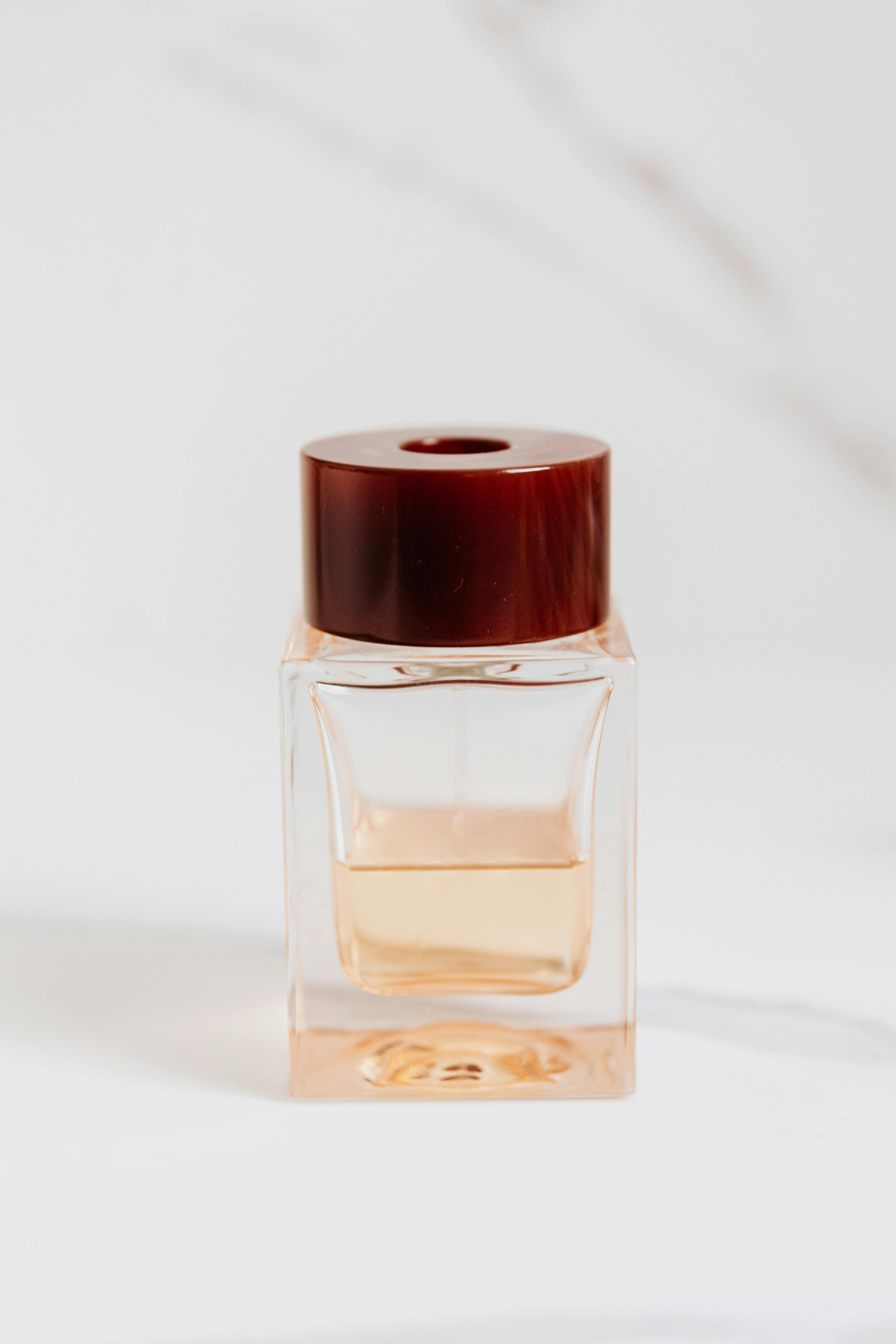 A Clear Glass Perfume Bottle With Brown Lid on White Surface · Free ...