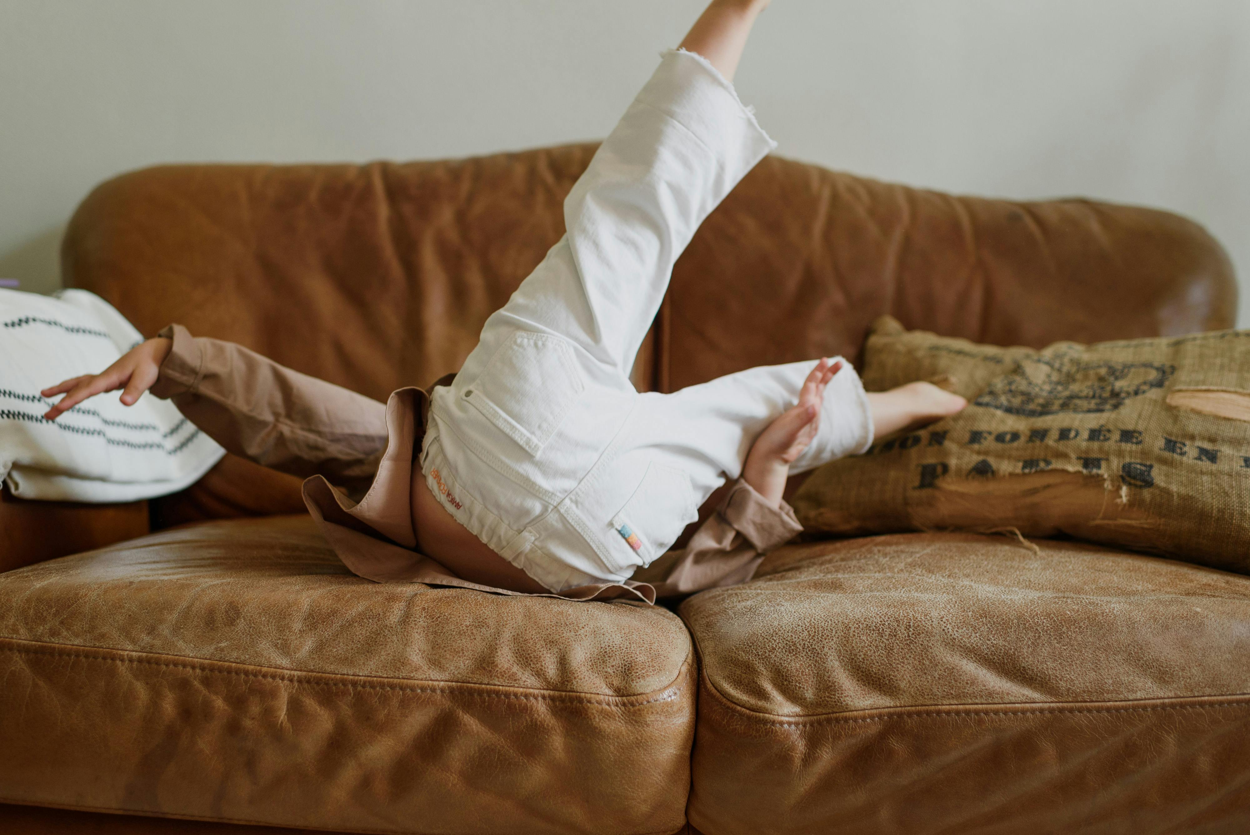 Excited girl jumping on couch in living room · Free Stock Photo