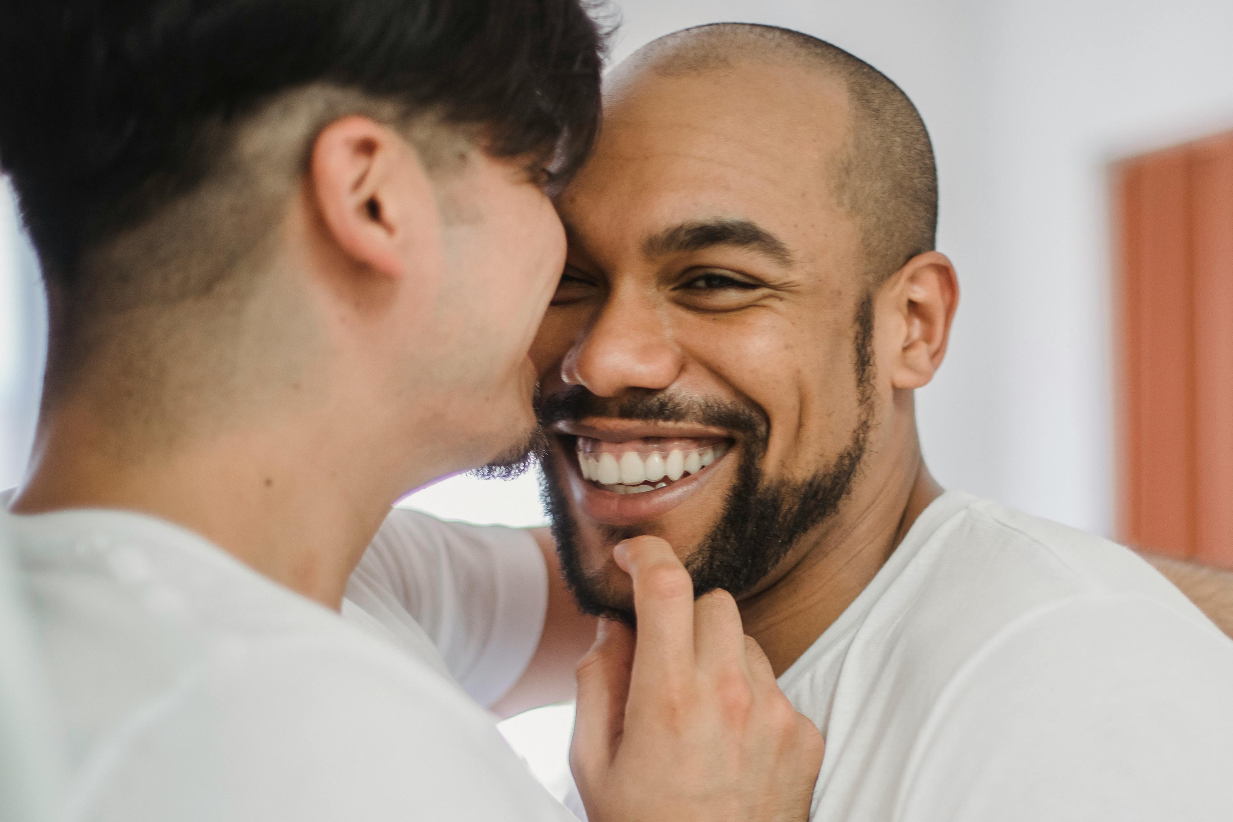 Young Man Smiling and Tickling Chin of Other Man · Free Stock Photo