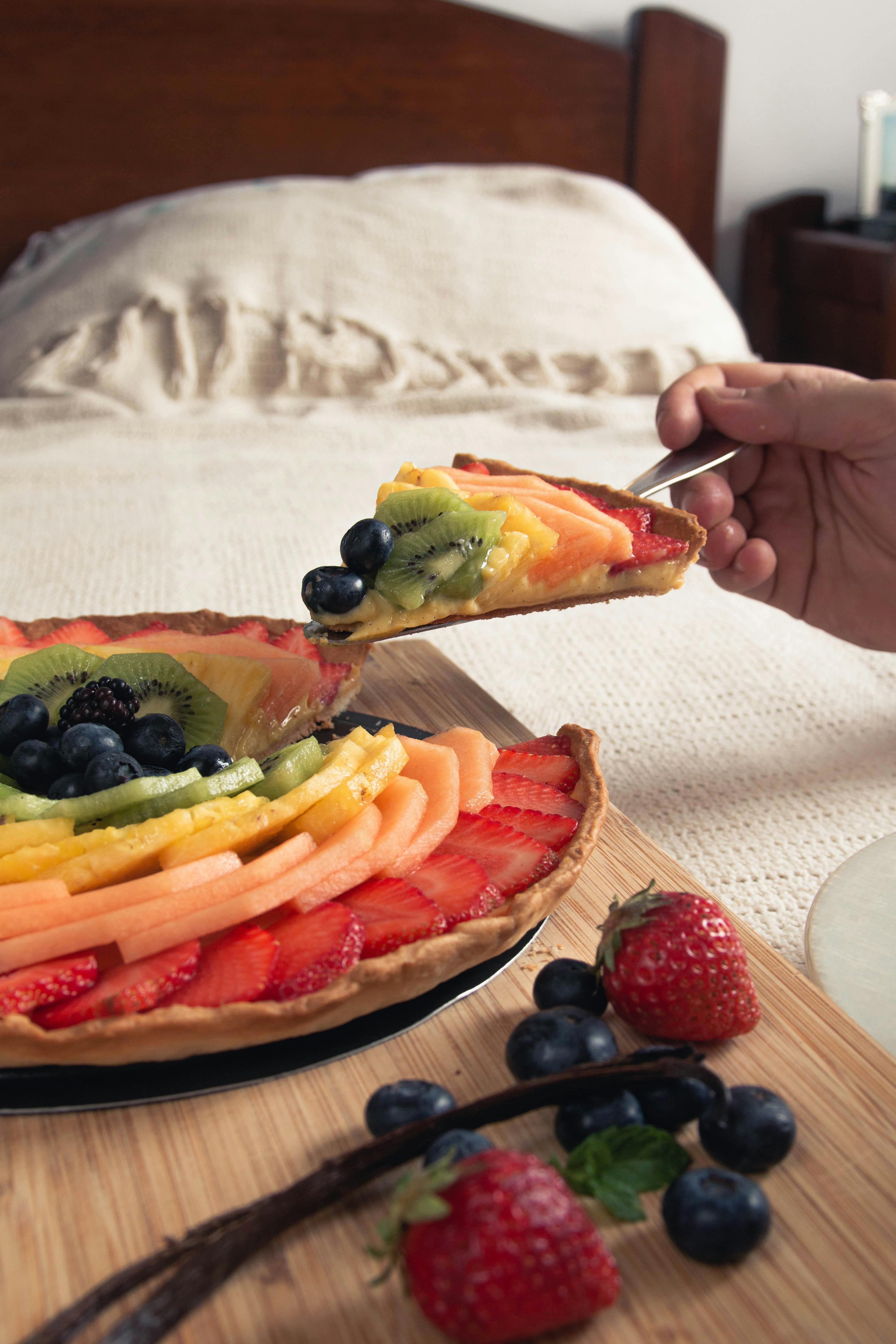 A Person Holding Sliced of Tart With Sliced of Fruits on Top · Free ...