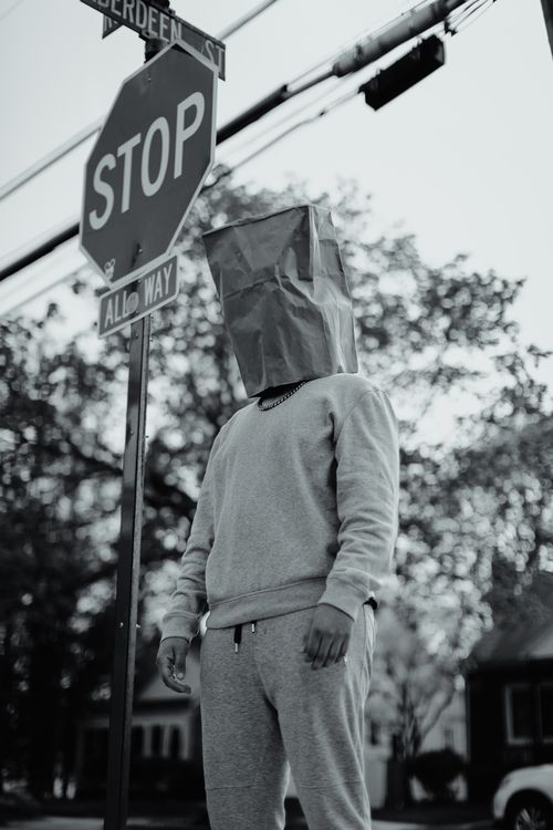 Grijstinten Foto Van Man In Jas Staande Op Stopbord · Gratis stockfoto